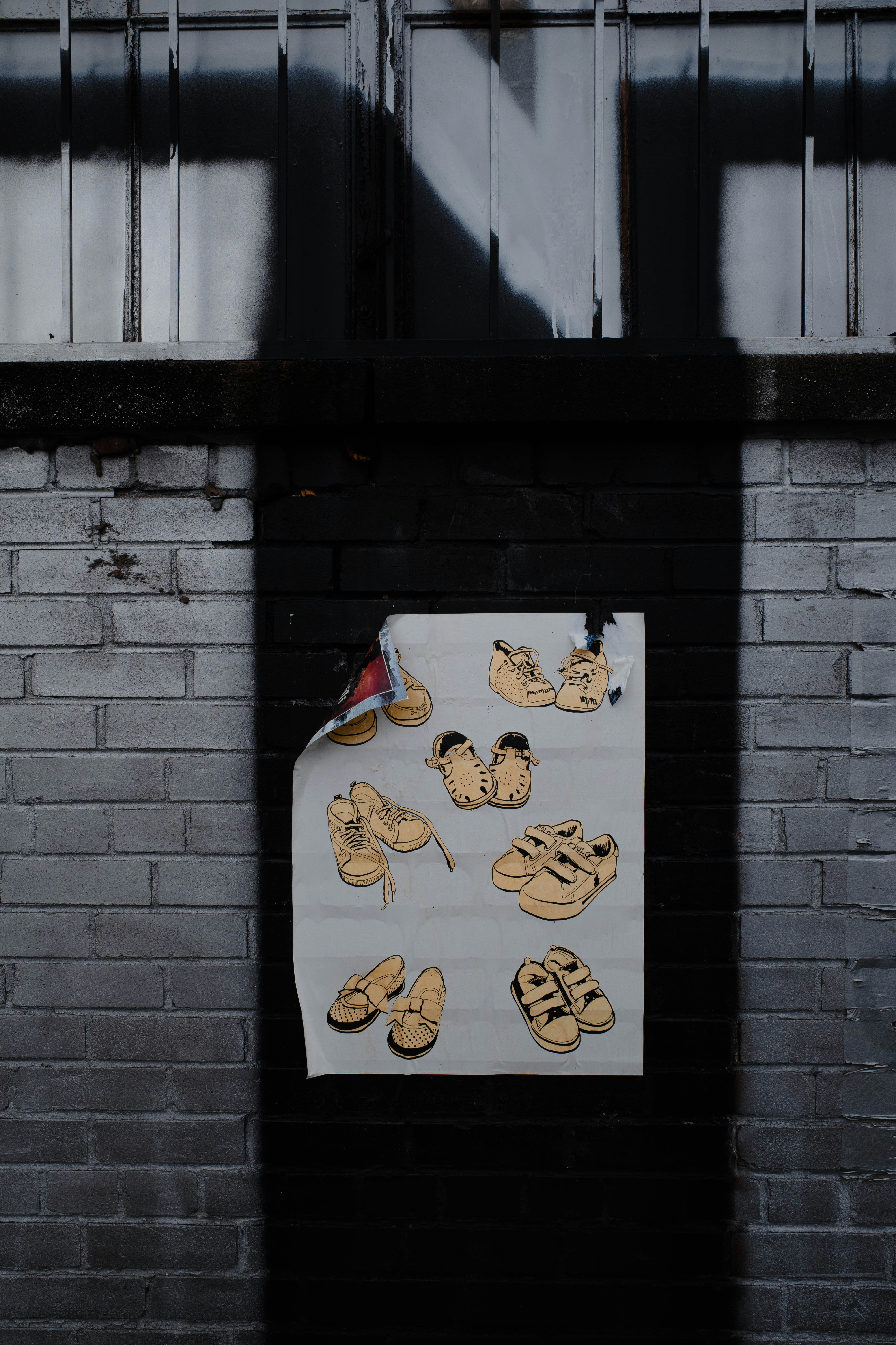 Shadowed doorway, a poster of shoes beneath the iron bars