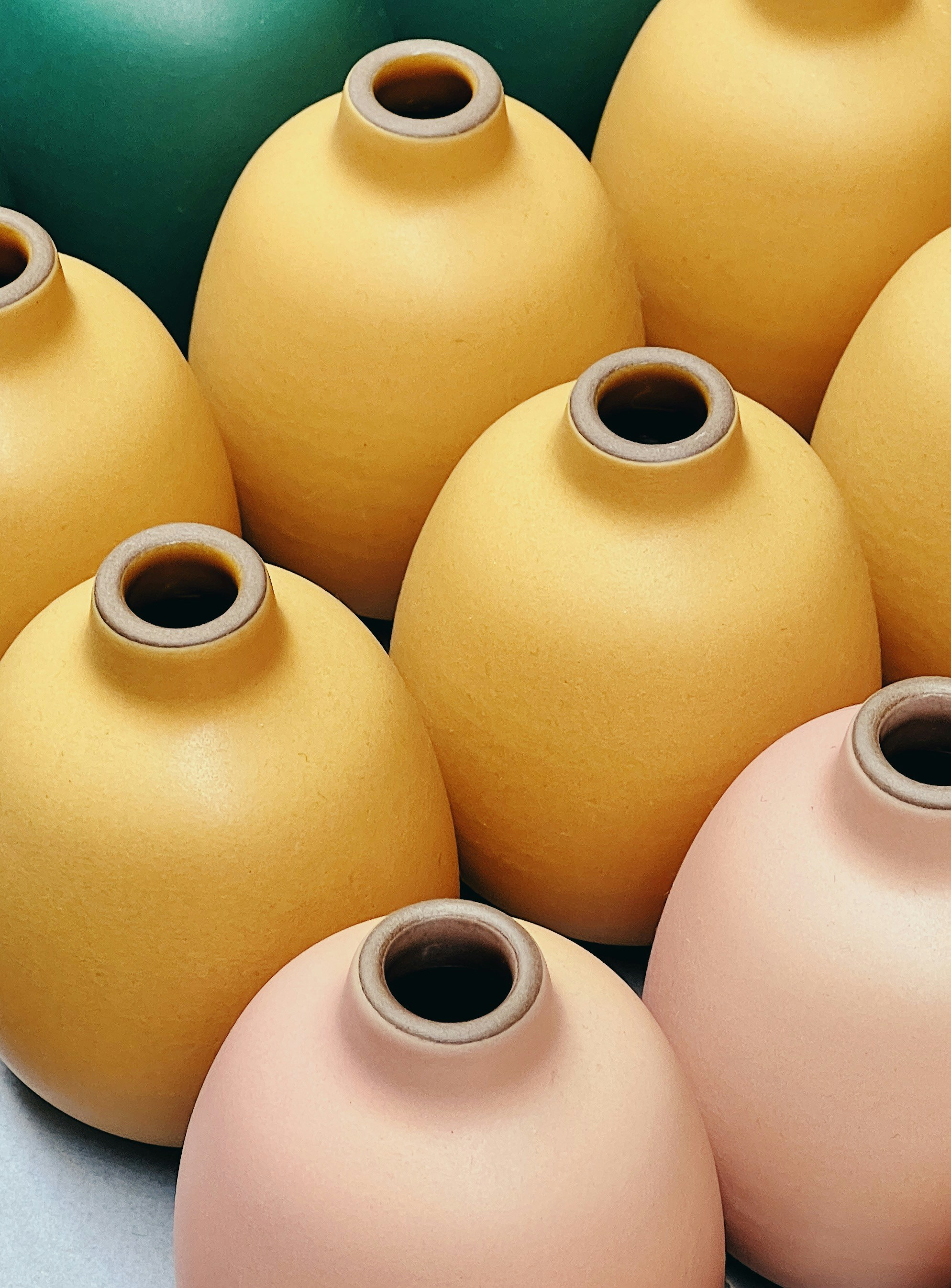 A collection of ceramic vases in soft pastel hues, arranged in a visually striking pattern. The varying shapes and colors create an intriguing composition.