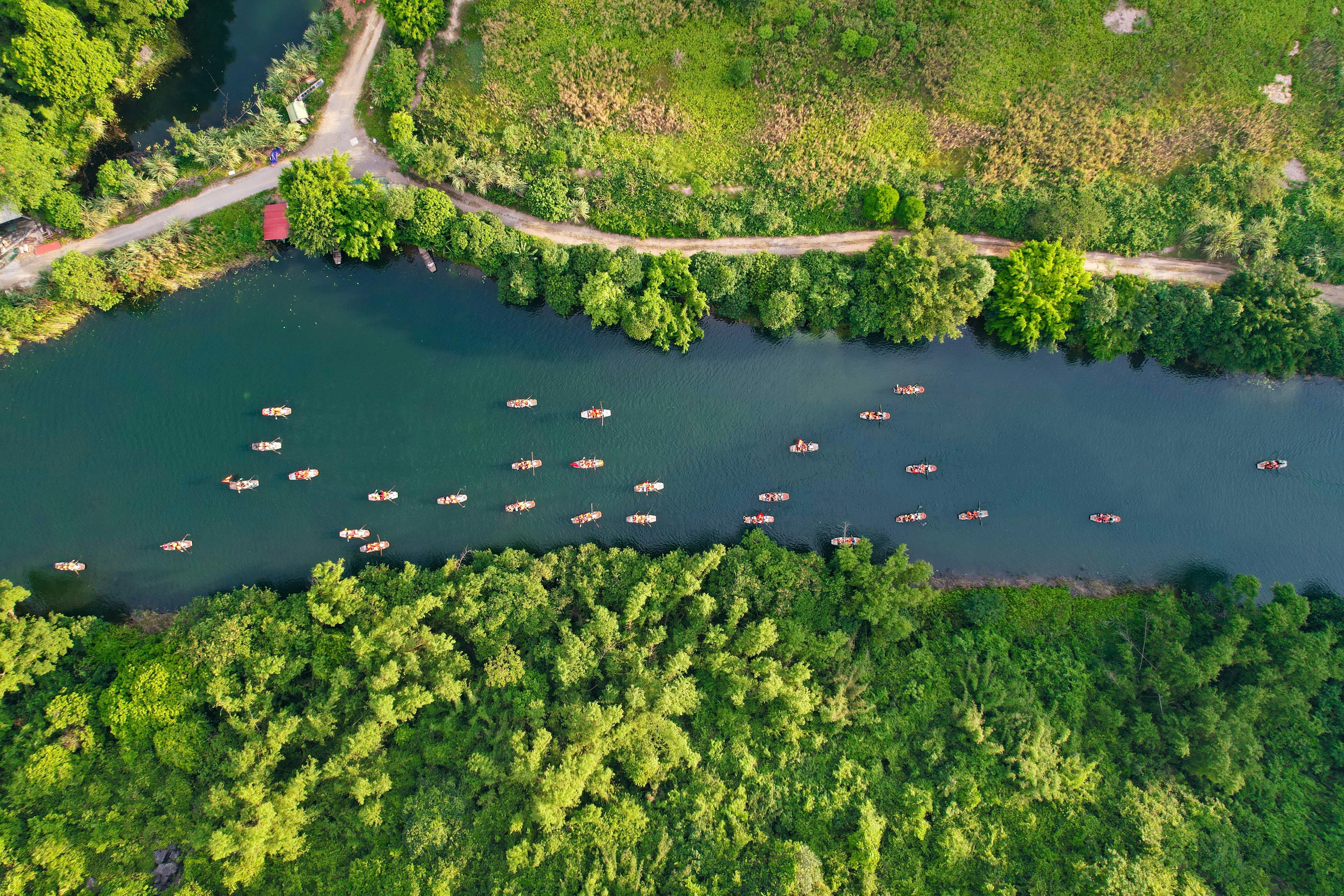Aerial view of boats dotting a winding river surrounded by lush greenery.