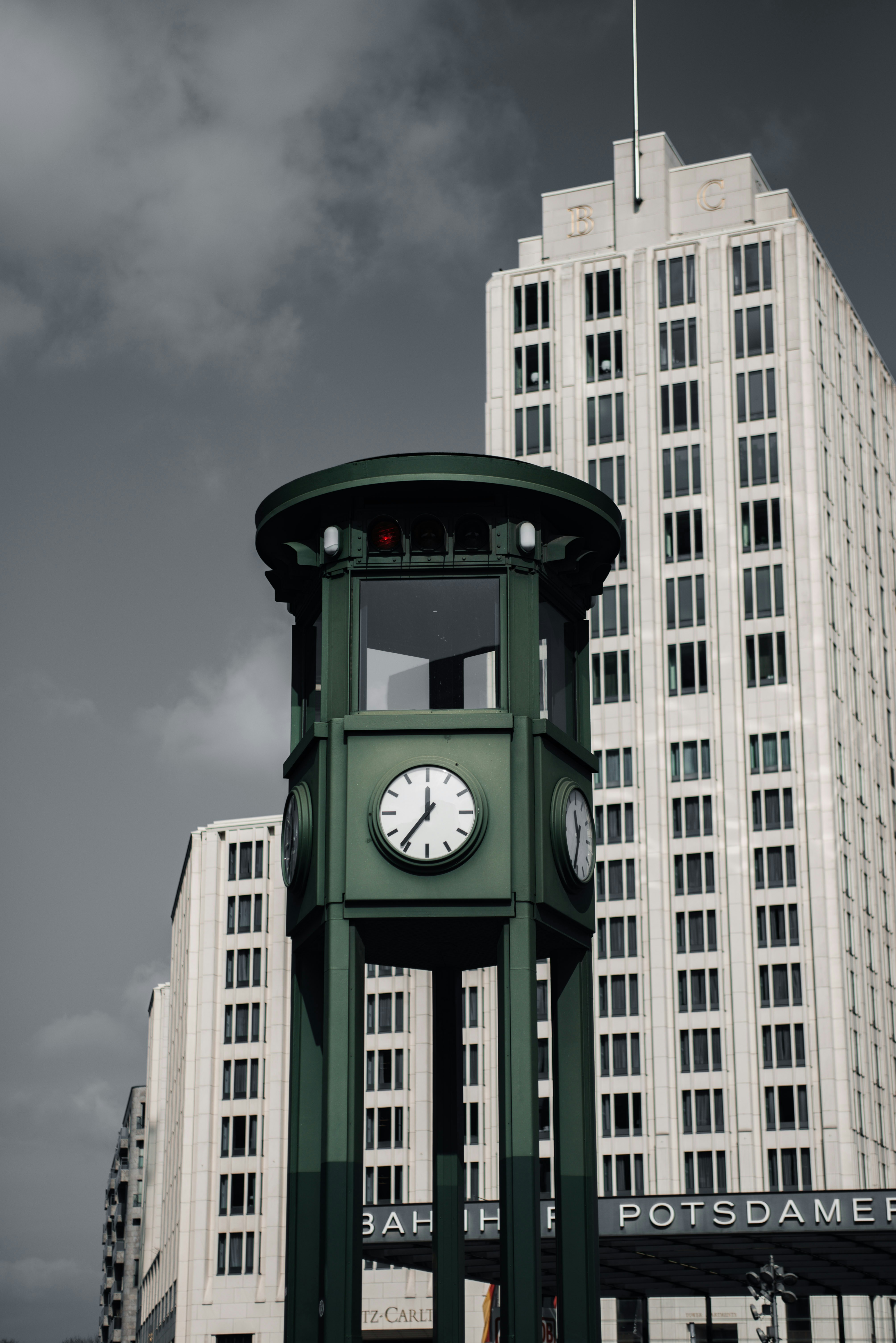 Emerald Clock Tower Standing Before a Grid of White Skyscrapers
