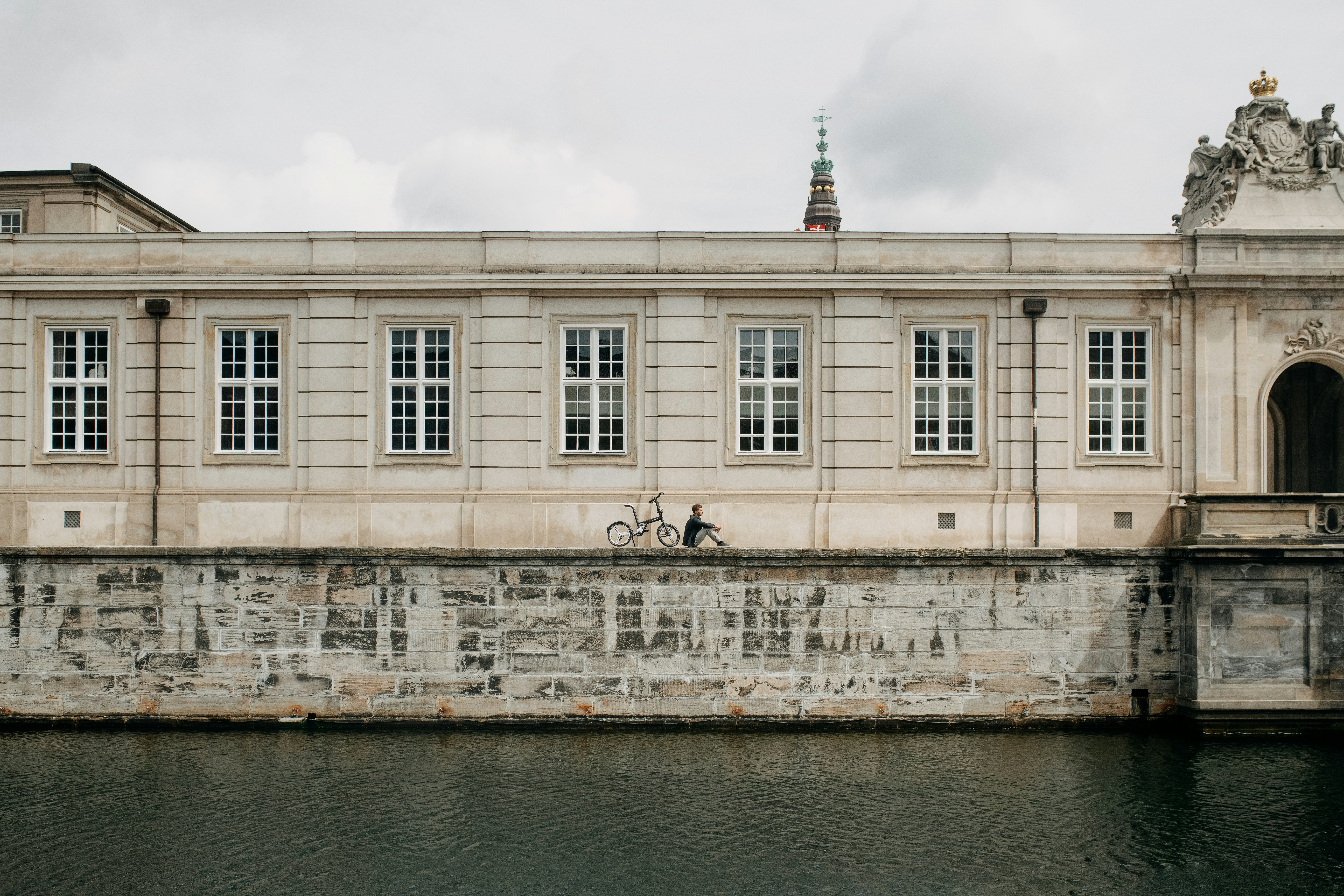 Rider on the Riverside Wall: A Quiet Moment Beside Neoclassical Facades