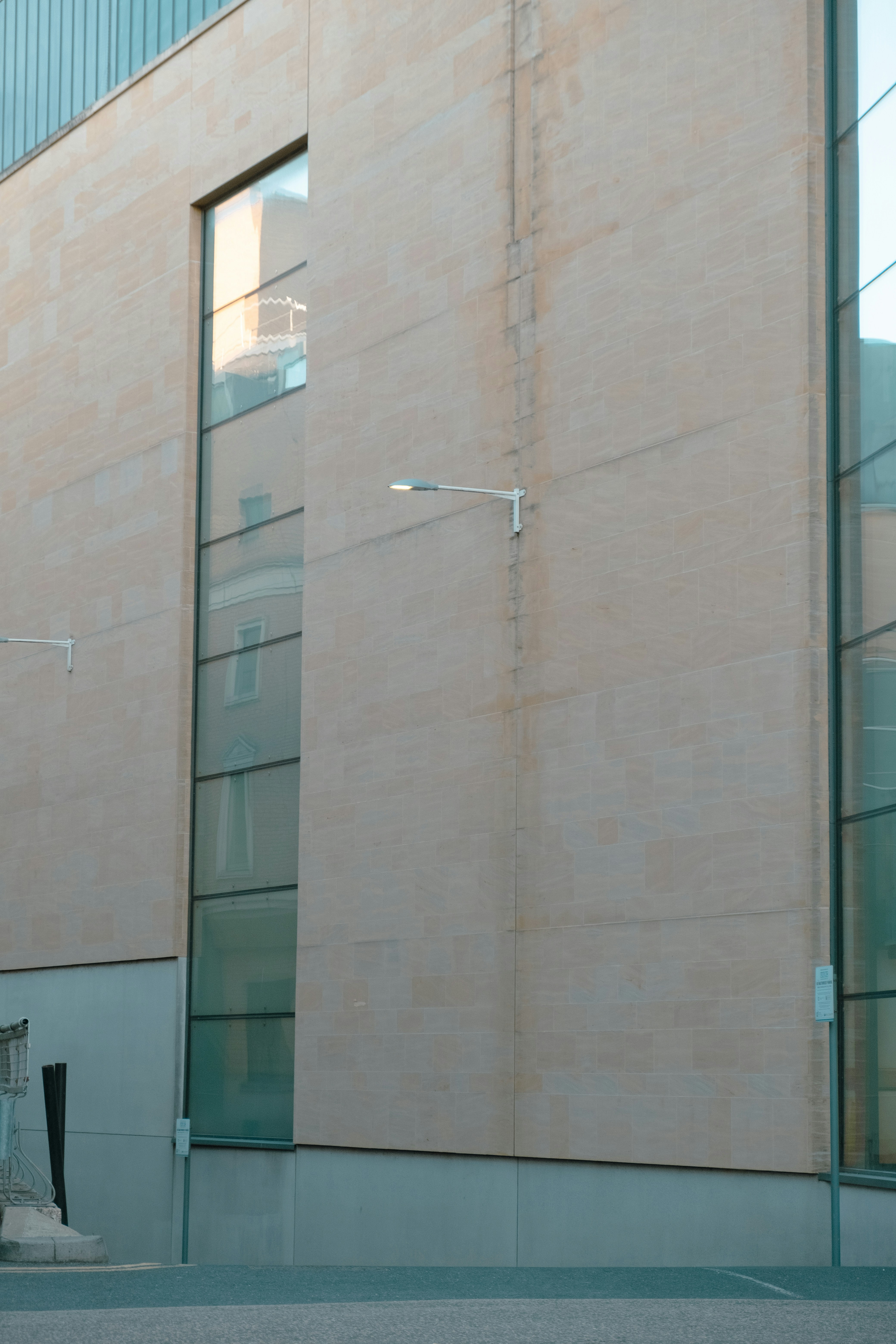 A sleek modern building facade featuring large glass windows and soft lighting, highlighting the interplay of reflections and textures.