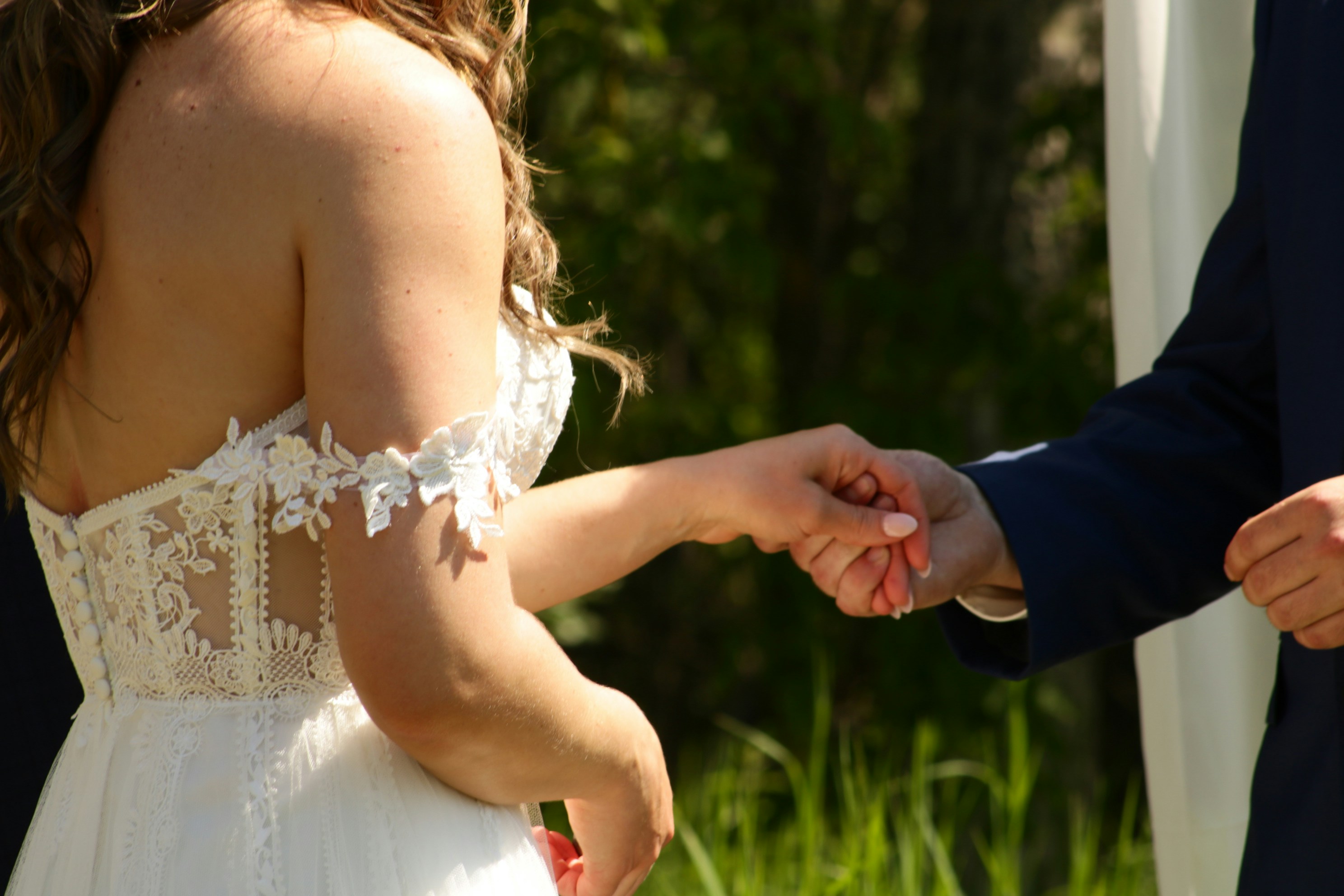 bride and groom holding hands at wedding ceremony | a person in a white dress