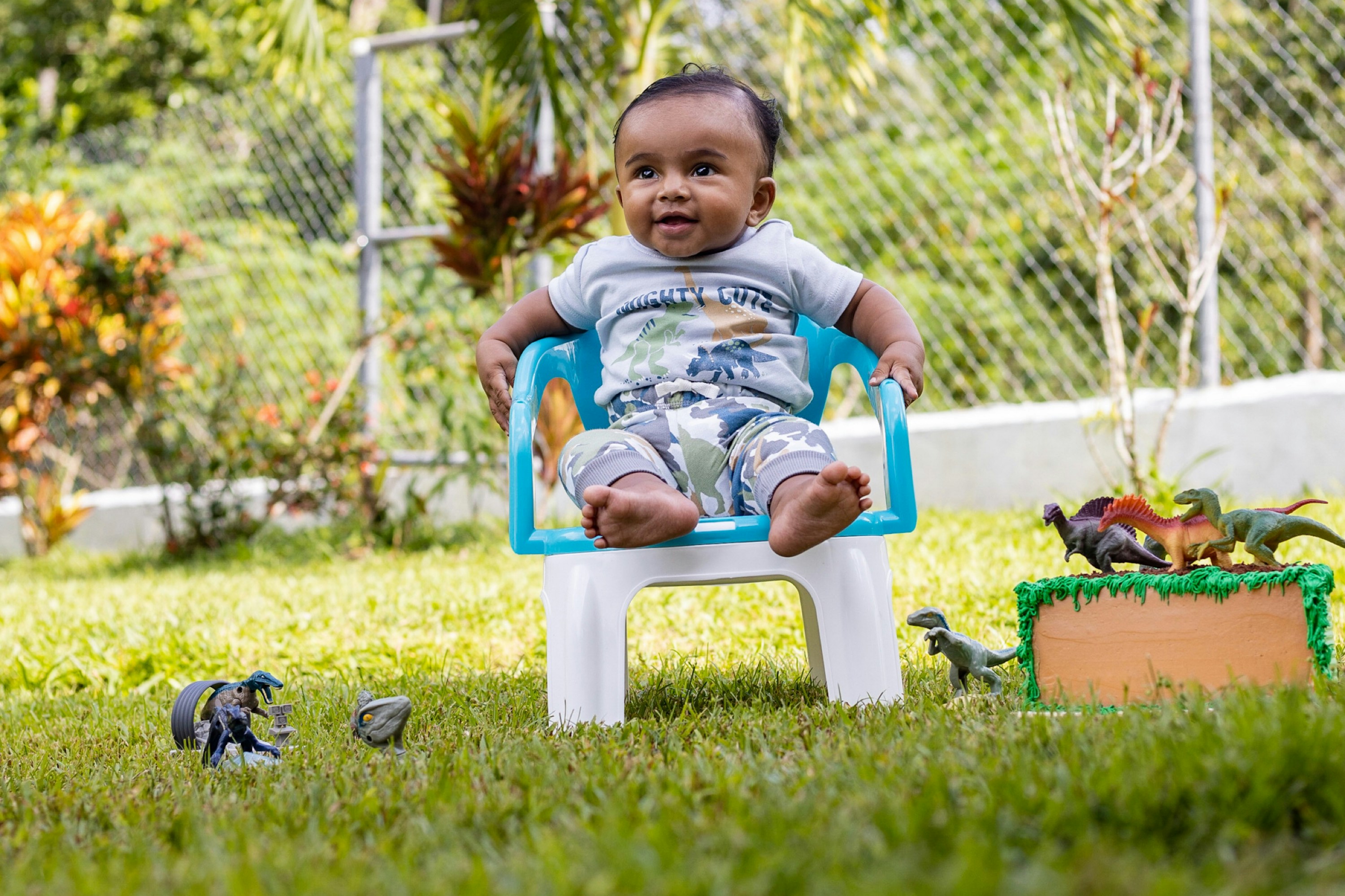 Sunny Backyard Swing: A Curious Baby Among Playful Dino Companions