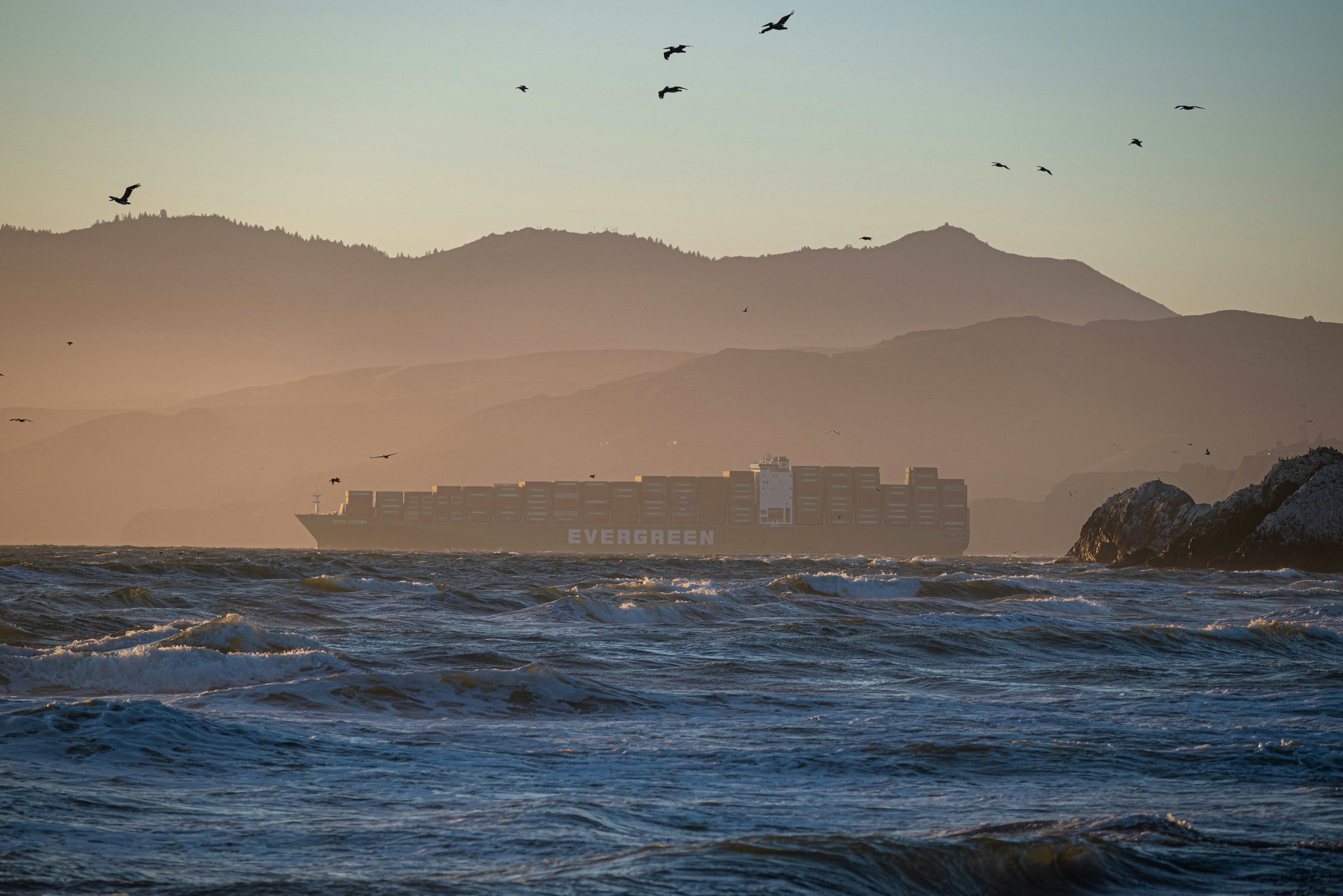 Dawn Mist Over the Evergreen: Container Ship on a Quiet Horizon