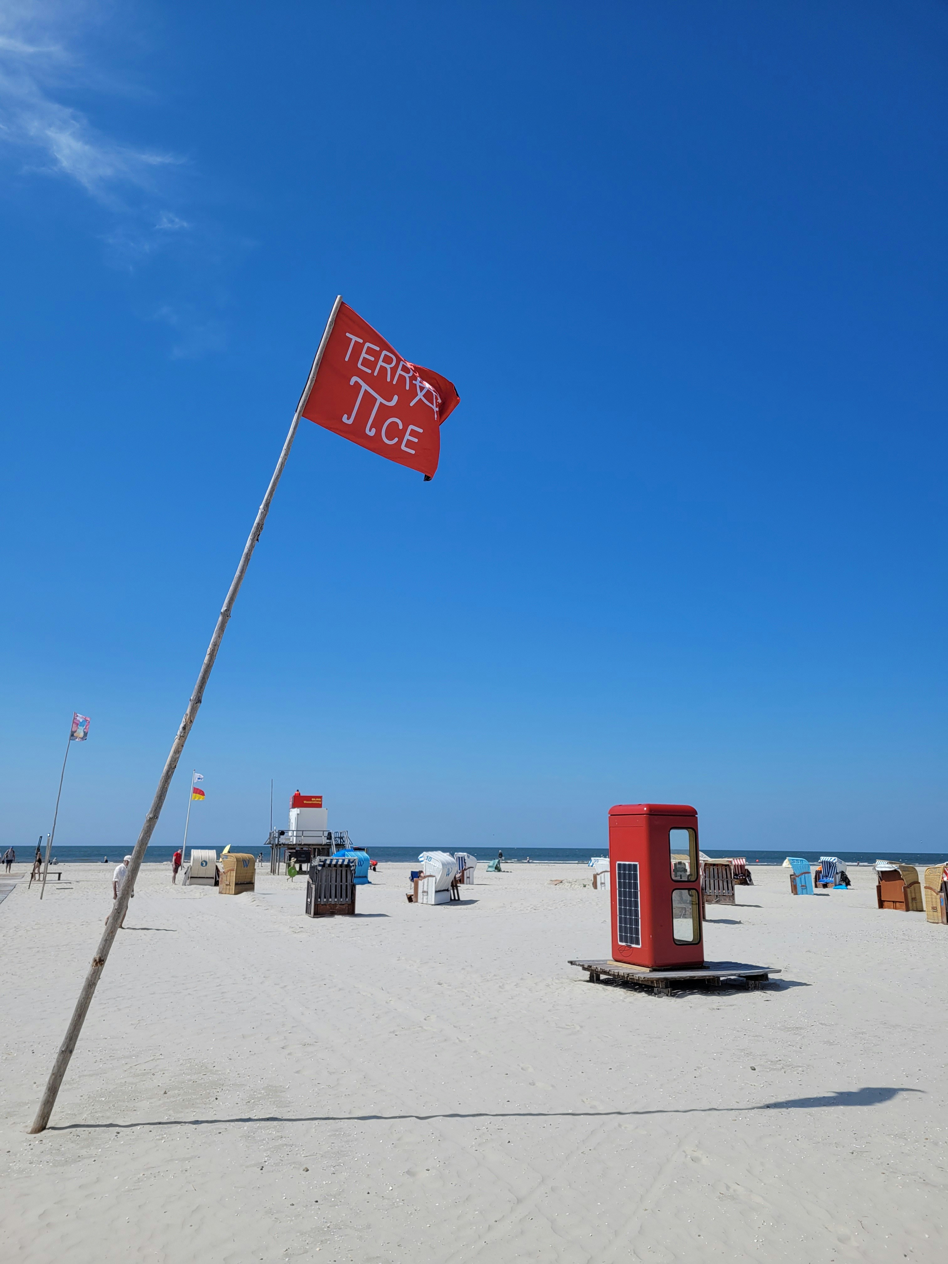 Tilted Red Flag at the Crest of a Quiet Coastal Scene