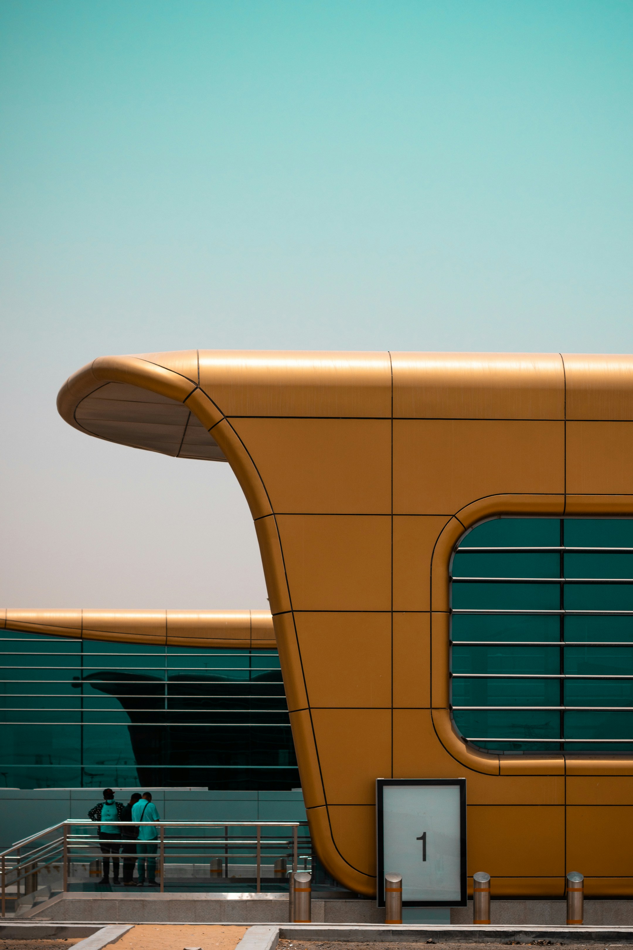 Winged Facade: Sunlit Curvature Against Teal Glass