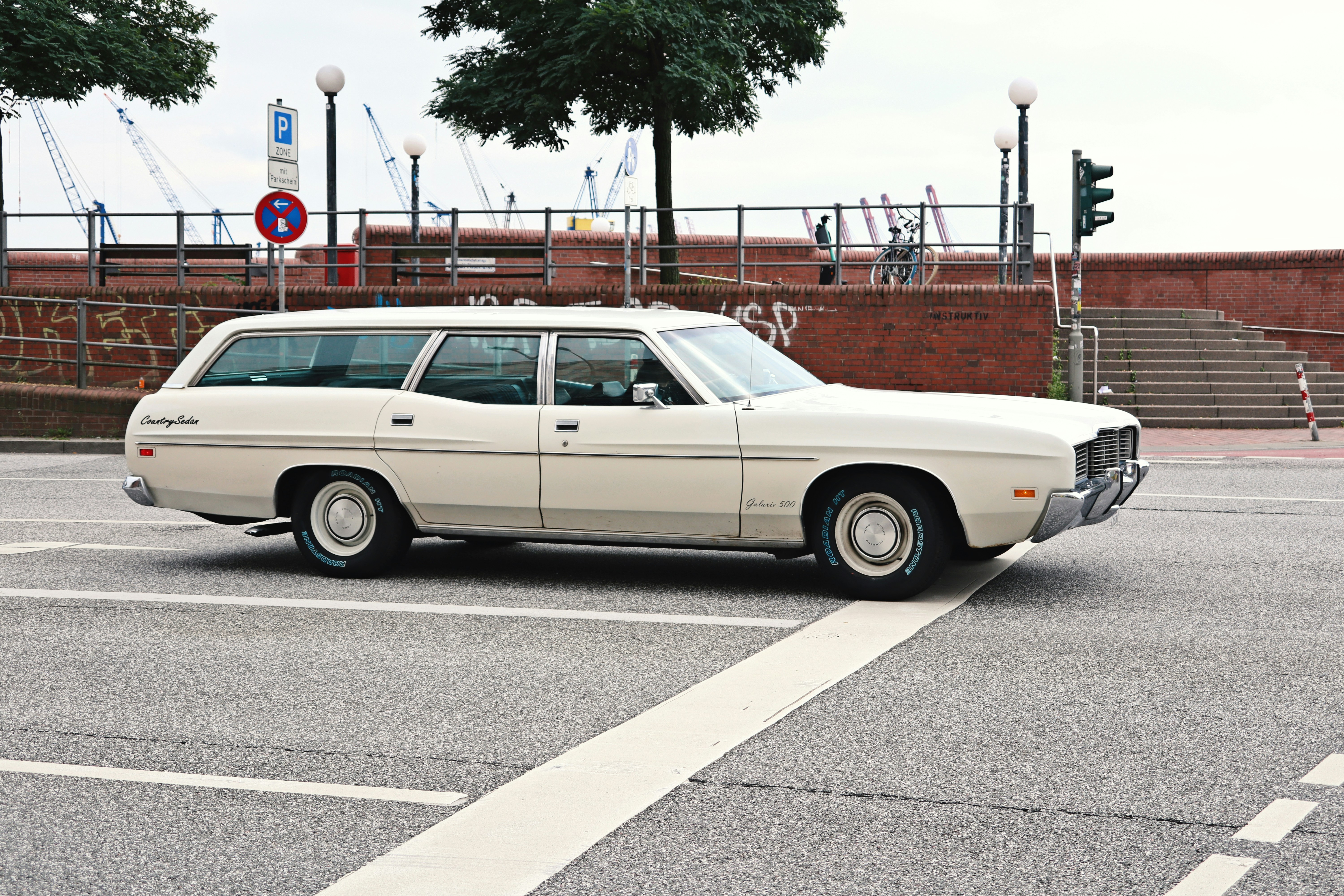 Vintage station wagon parked at a city intersection, showcasing its retro design against a modern backdrop.