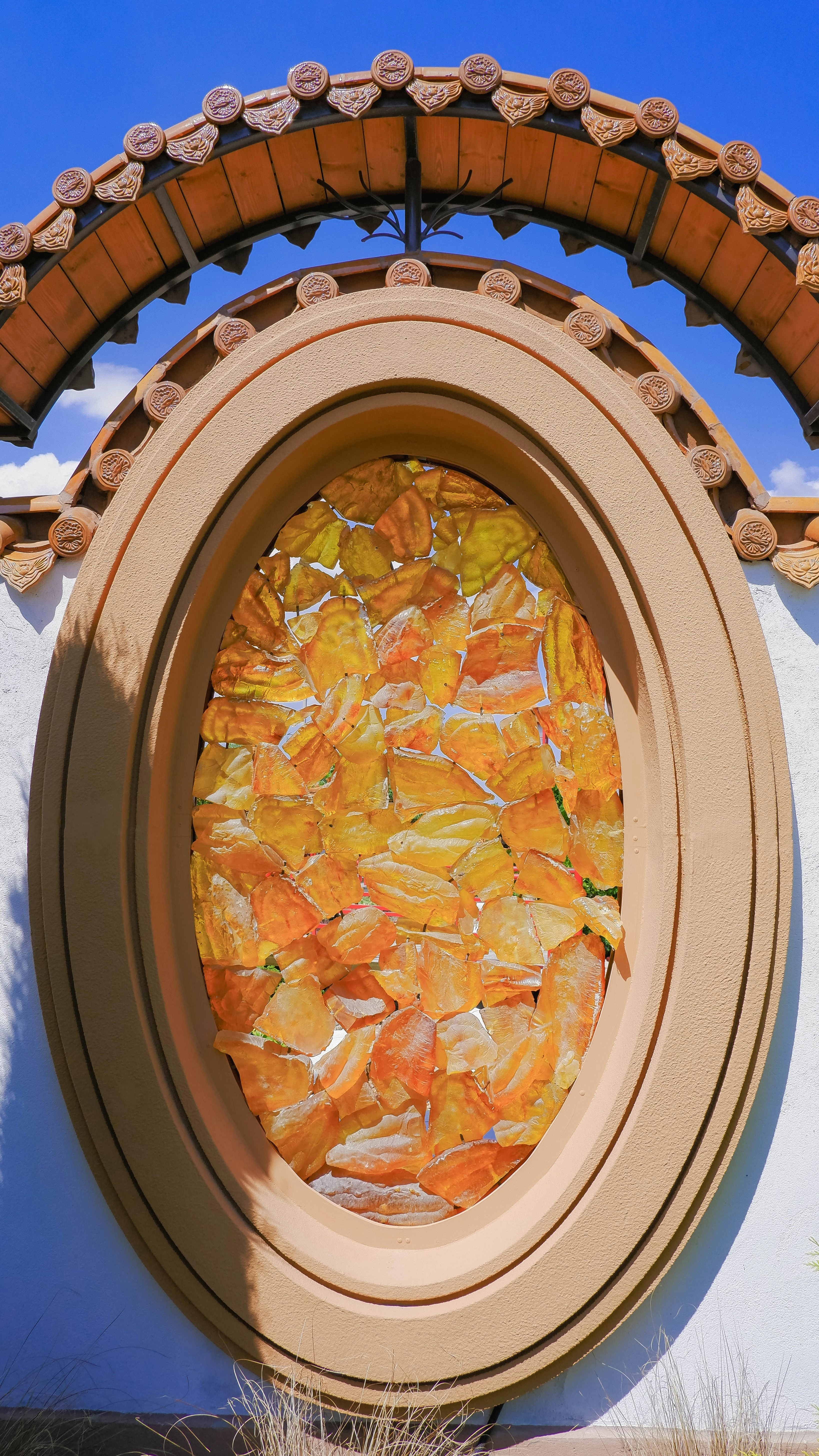 Amber Mosaic Oval: A Sunlit Archway Window Framed in Desert Clay