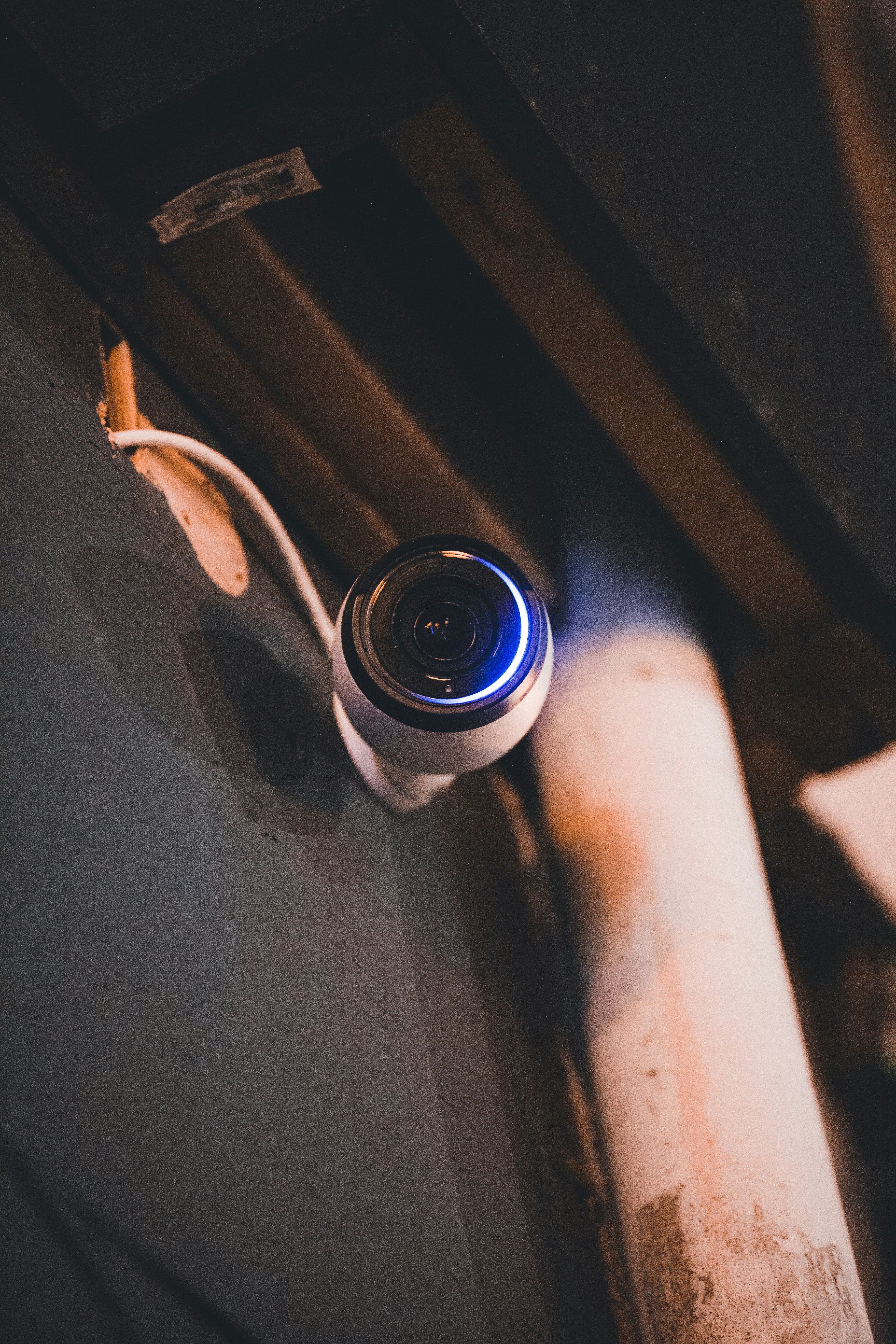 Dome Gazer in the Basement: A close-up of a white surveillance camera amid pipes and shadows