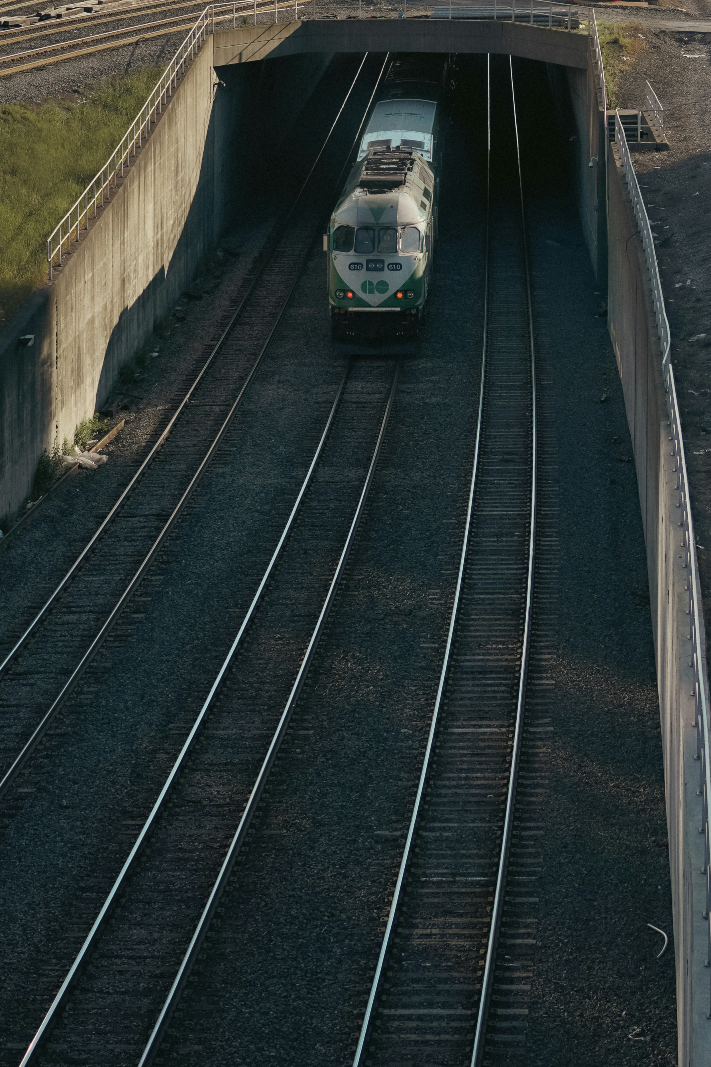 Approaching the Tunnel: Silver locomotive enters the underpass from an elevated vantage