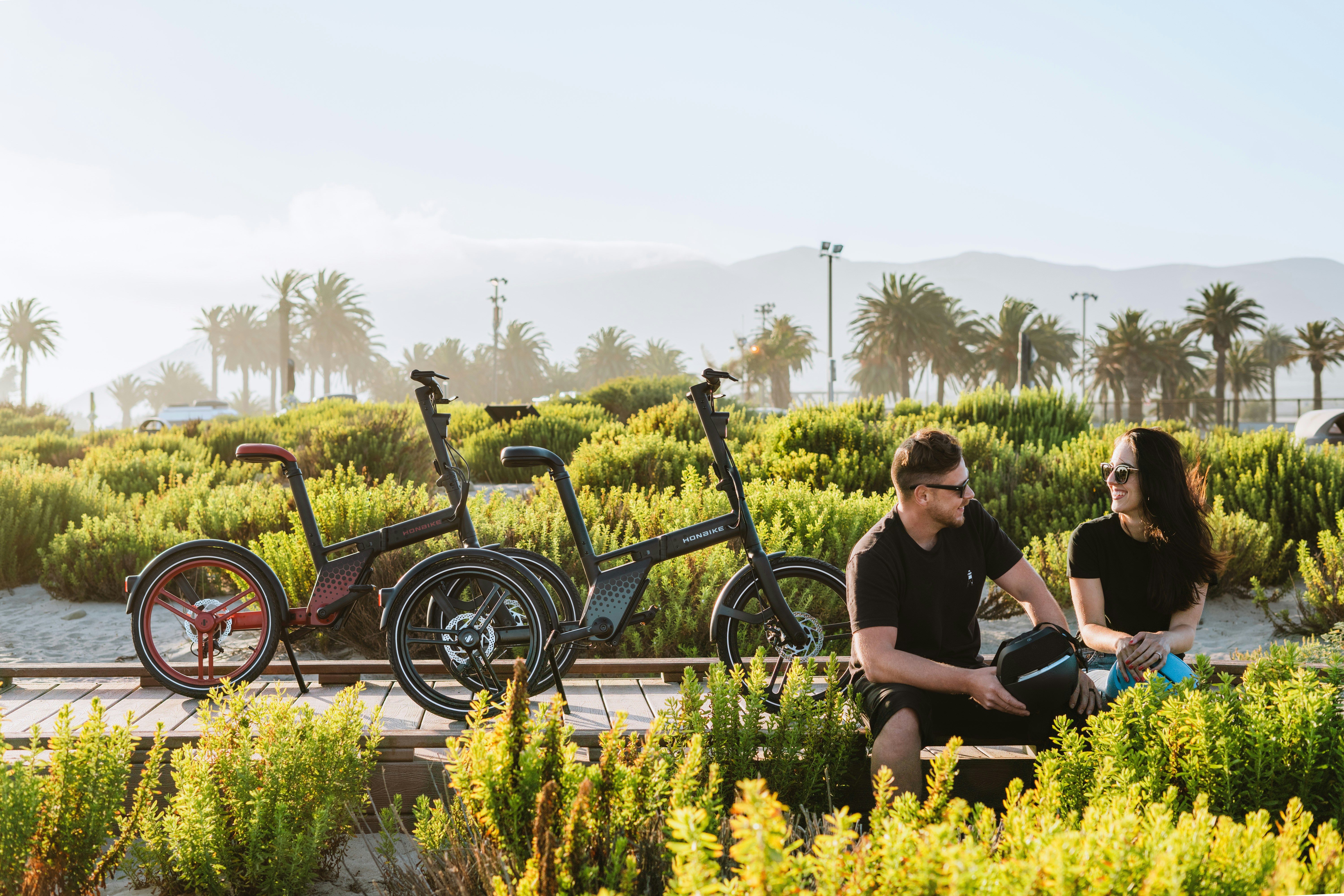A couple of people sit on a bench next to some bikes photo – Free Shaft ...