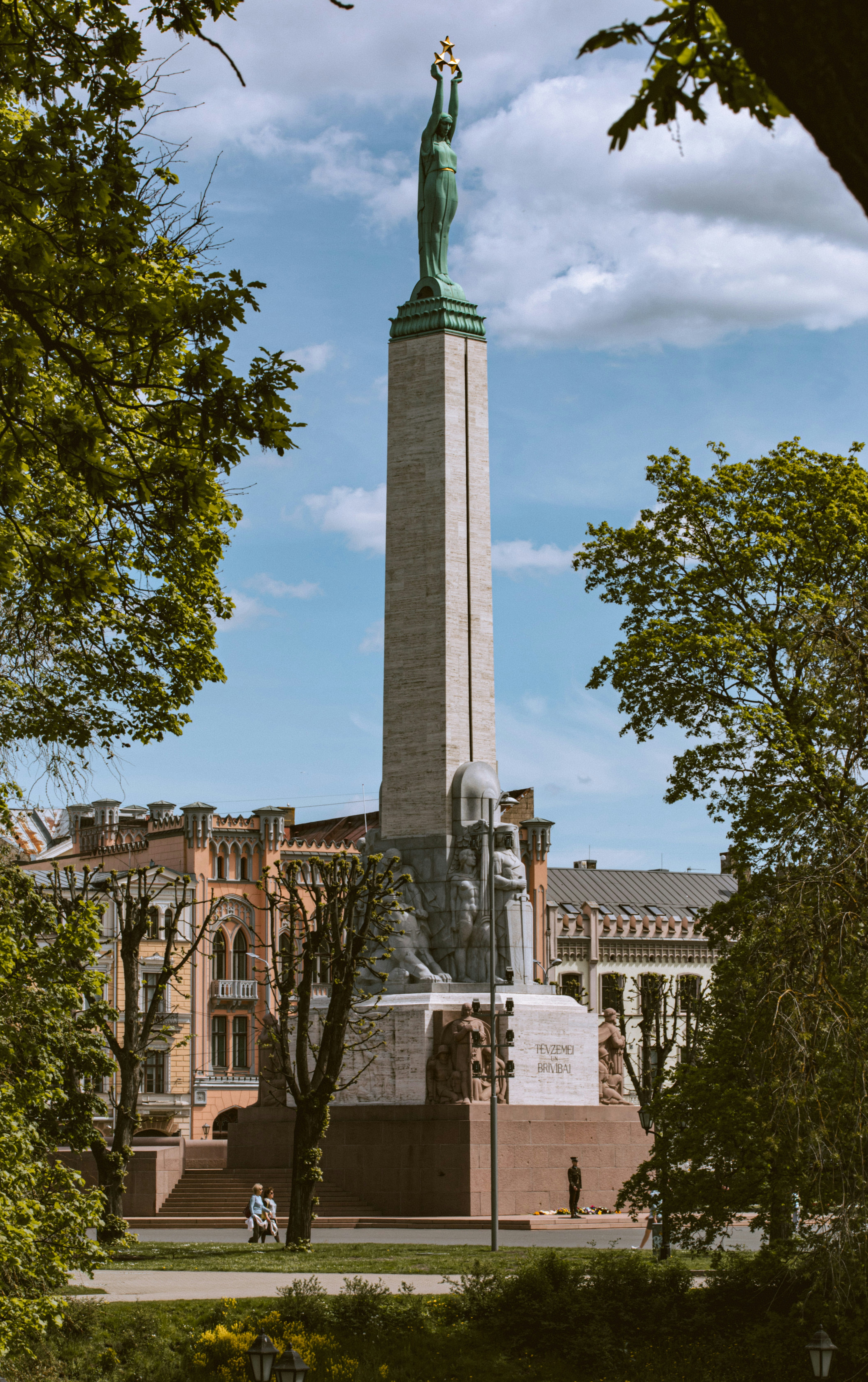 Skyward Sentinel: Patinaed Statue Crowned atop a City Monument