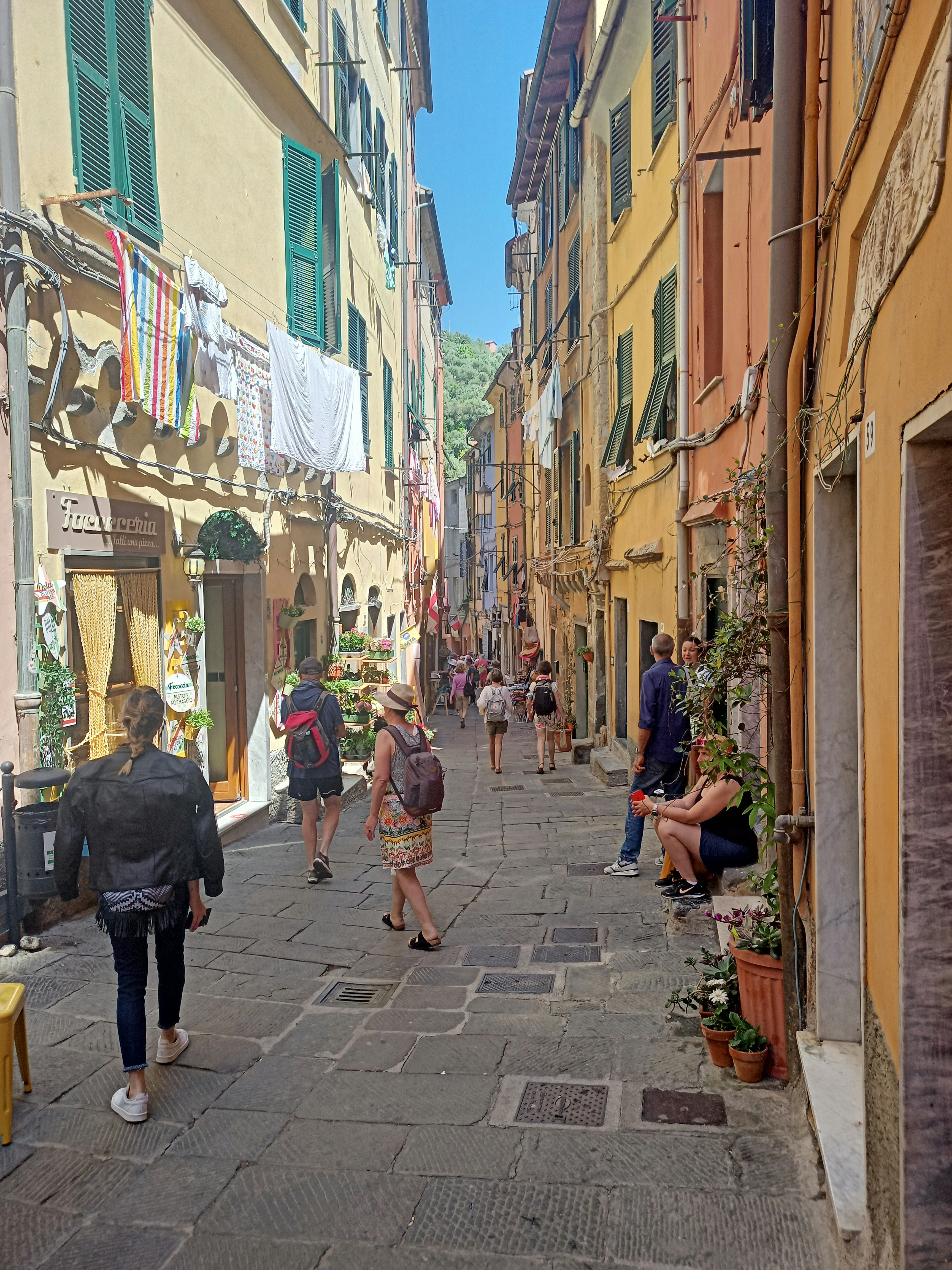 Bustling narrow street lined with vibrant buildings and hanging laundry, showcasing a lively atmosphere in a picturesque town.