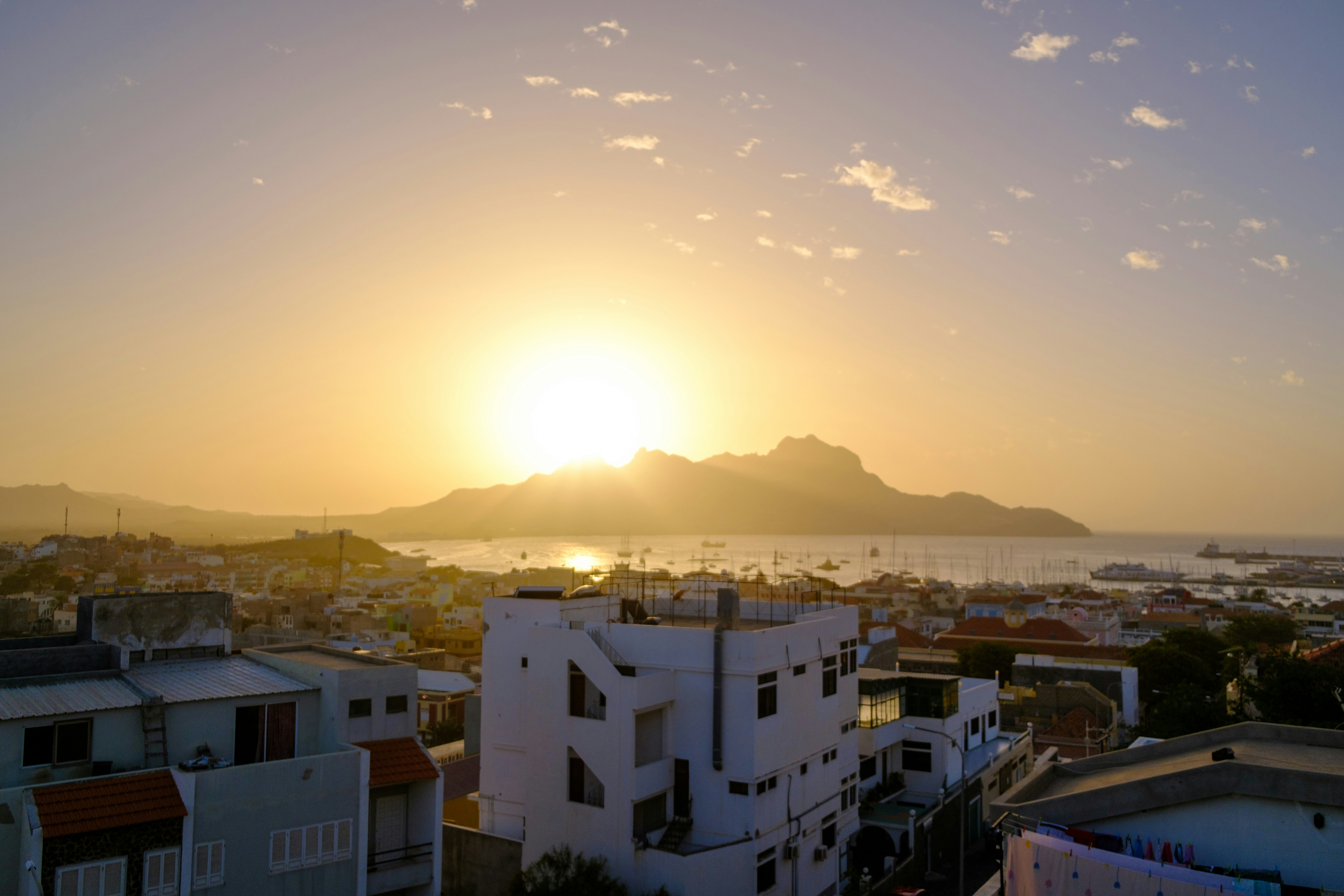 Sunset casts a warm glow over Monte Cara in Mindelo, silhouetting the mountain against a vibrant sky.