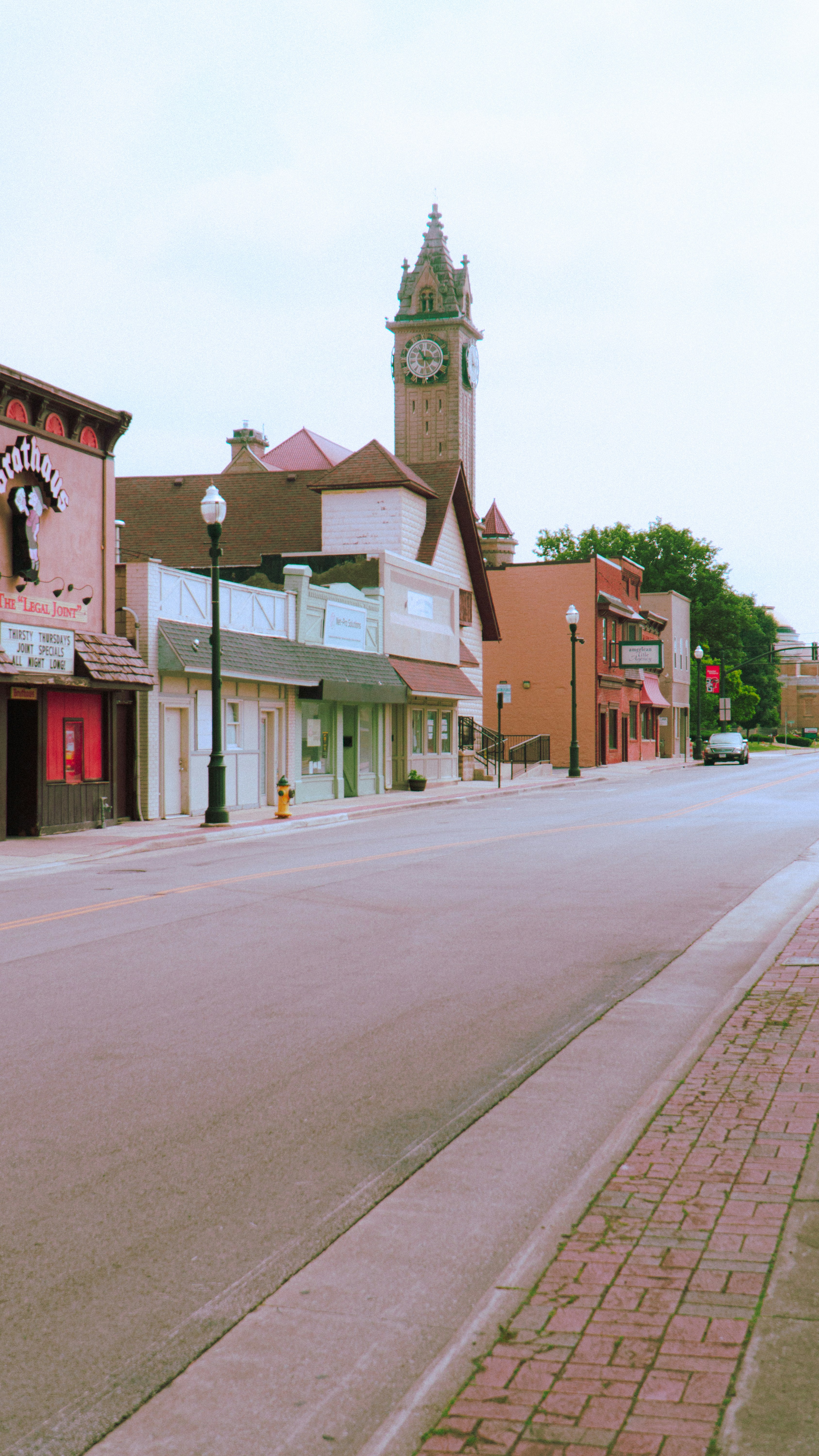 Historic clock tower stands tall above a quiet street lined with charming storefronts, capturing the essence of a bygone era.