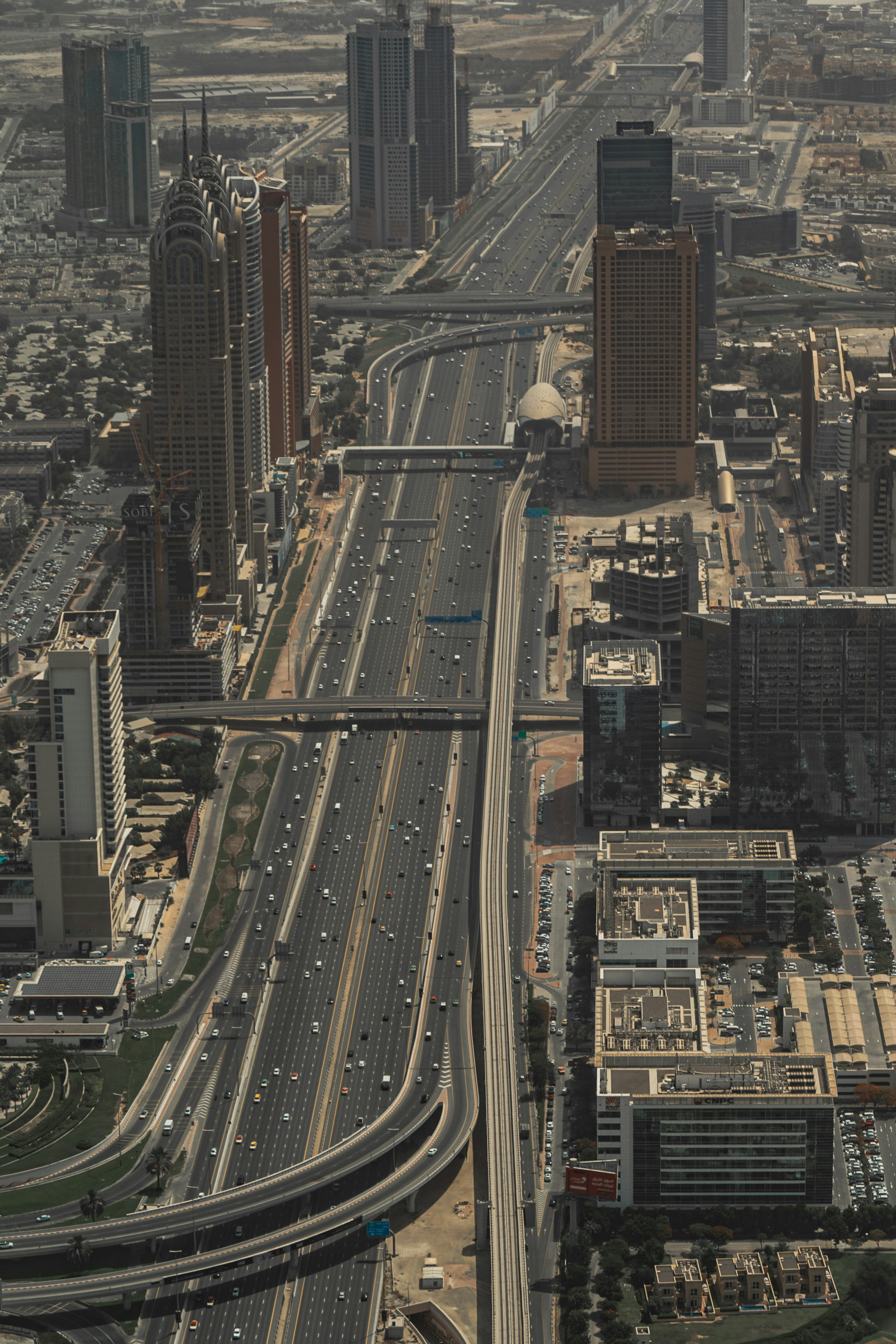 Aerial view showcasing a bustling highway flanked by modern skyscrapers, illustrating the vibrant urban landscape. The intricate road network highlights the city's dynamic flow.