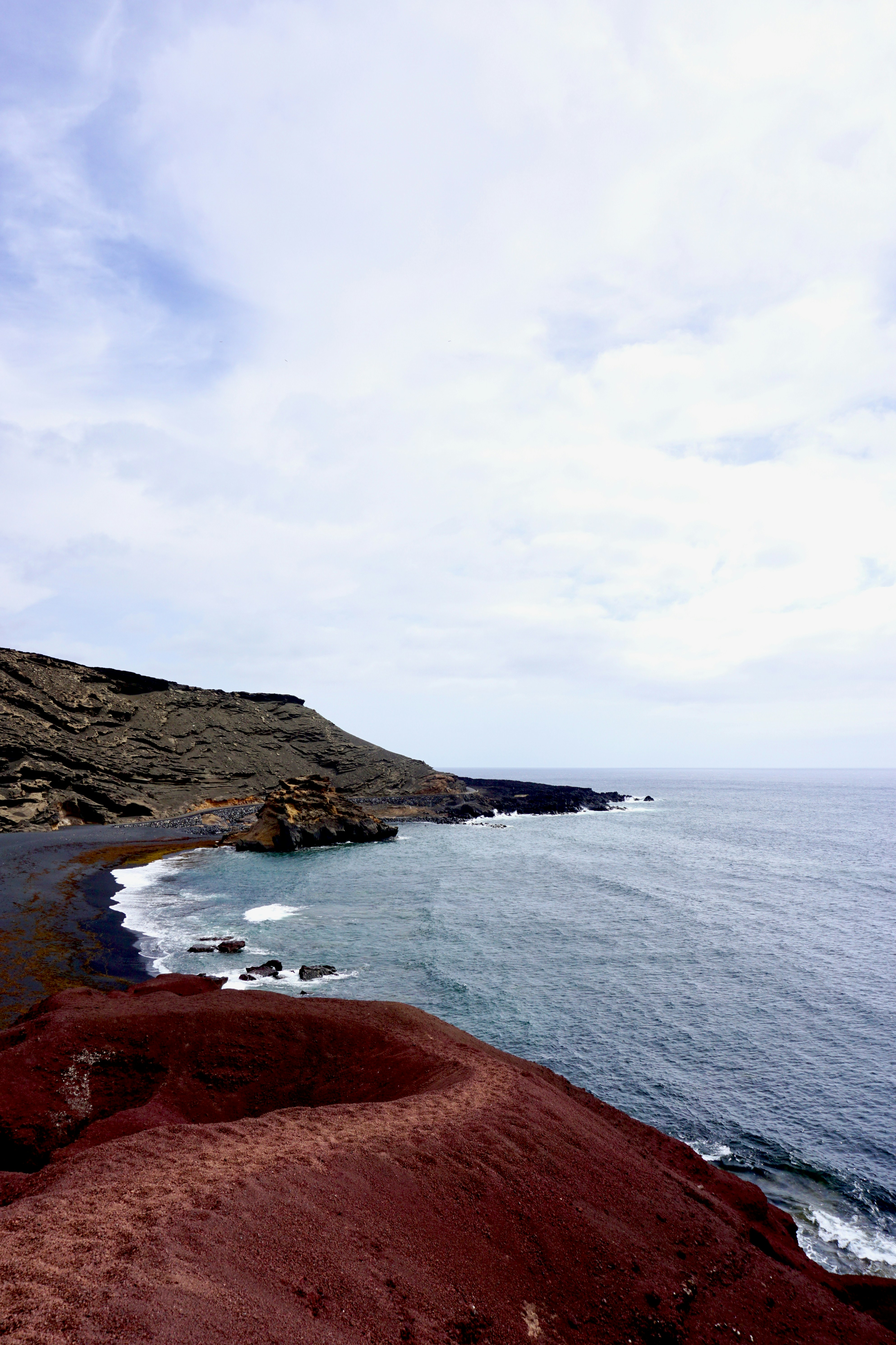 a rocky beach with a body of water in the background