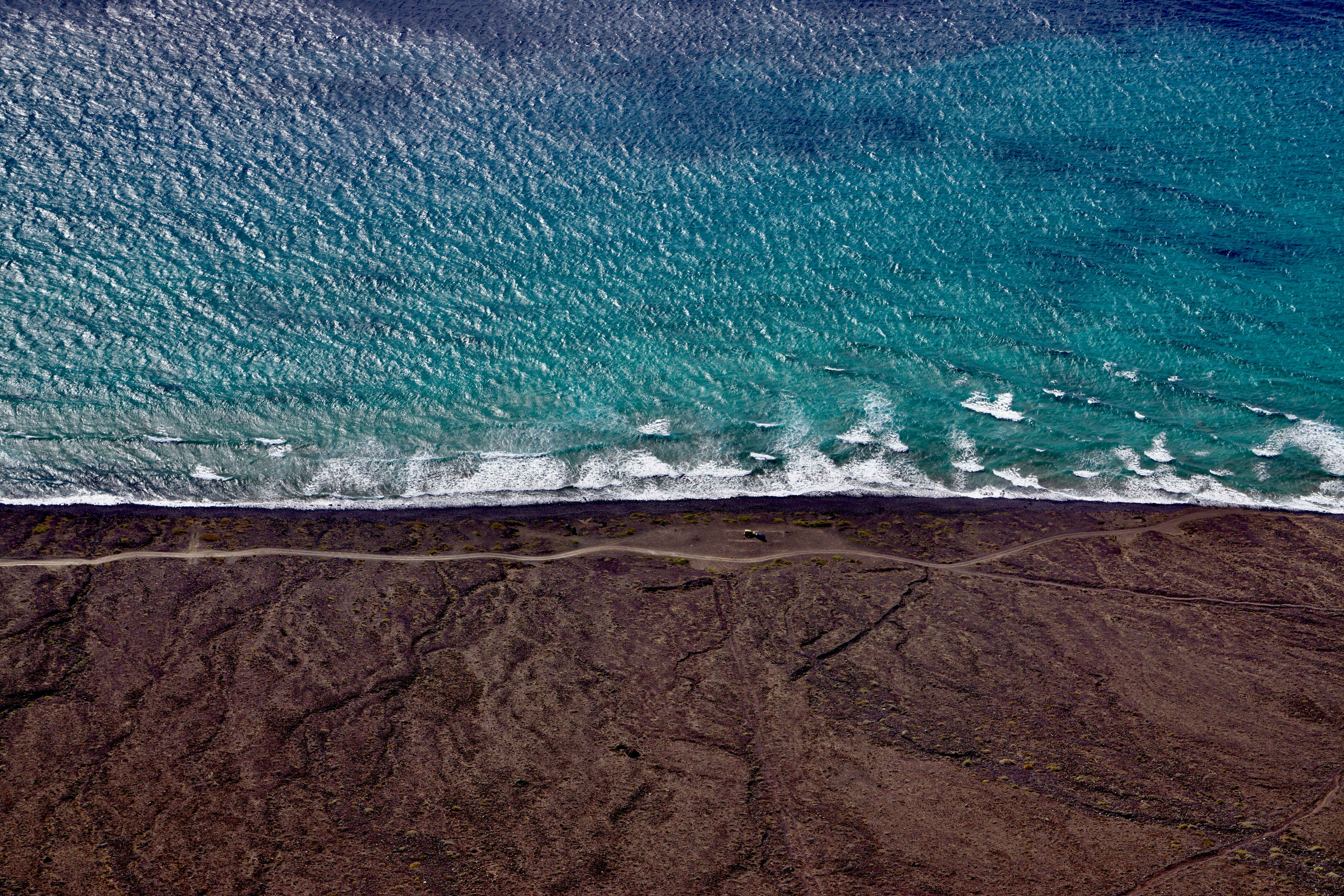 Shoreline Veins: Aerial View of Waves Meeting Dark Sand