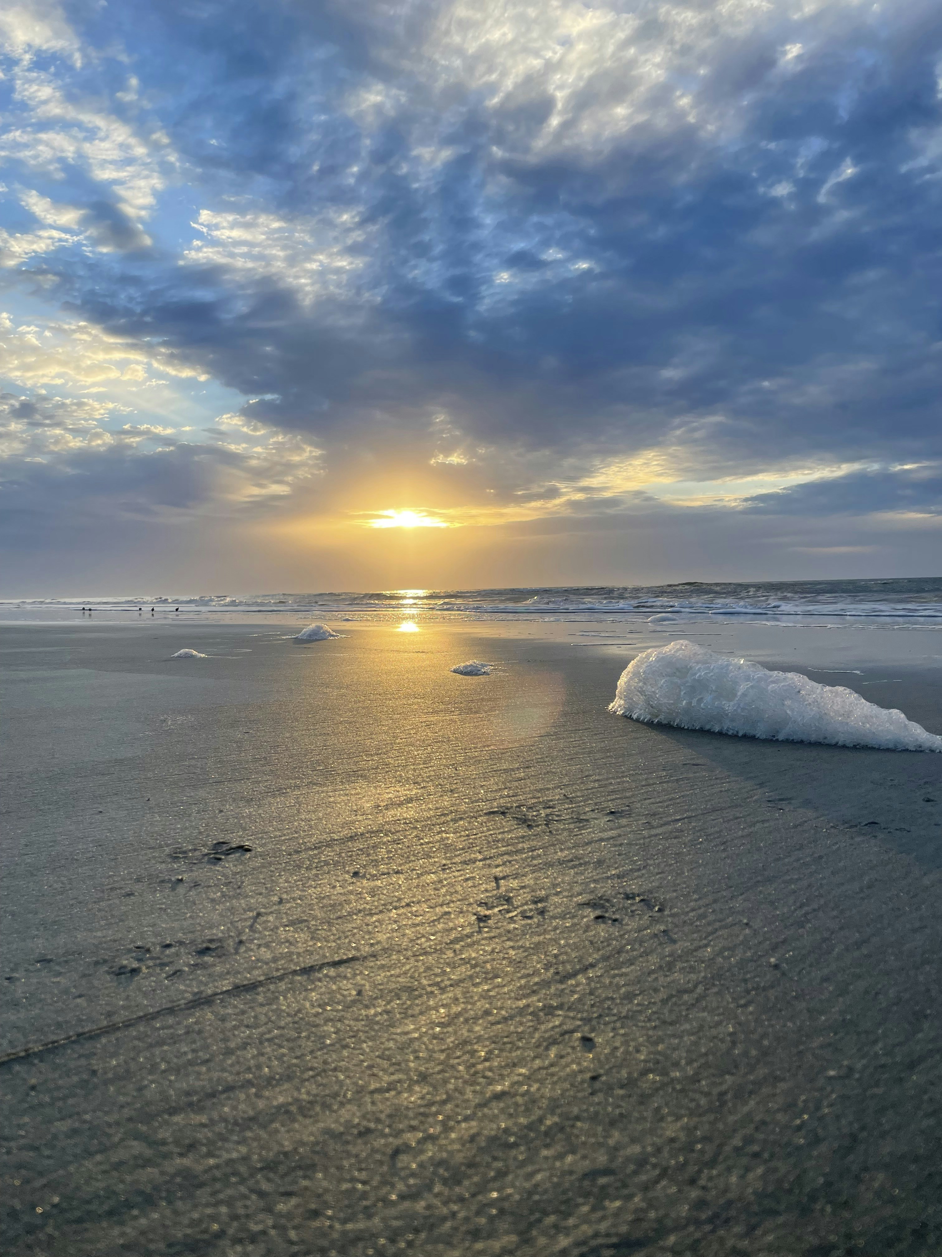 a beach with waves and the sun setting