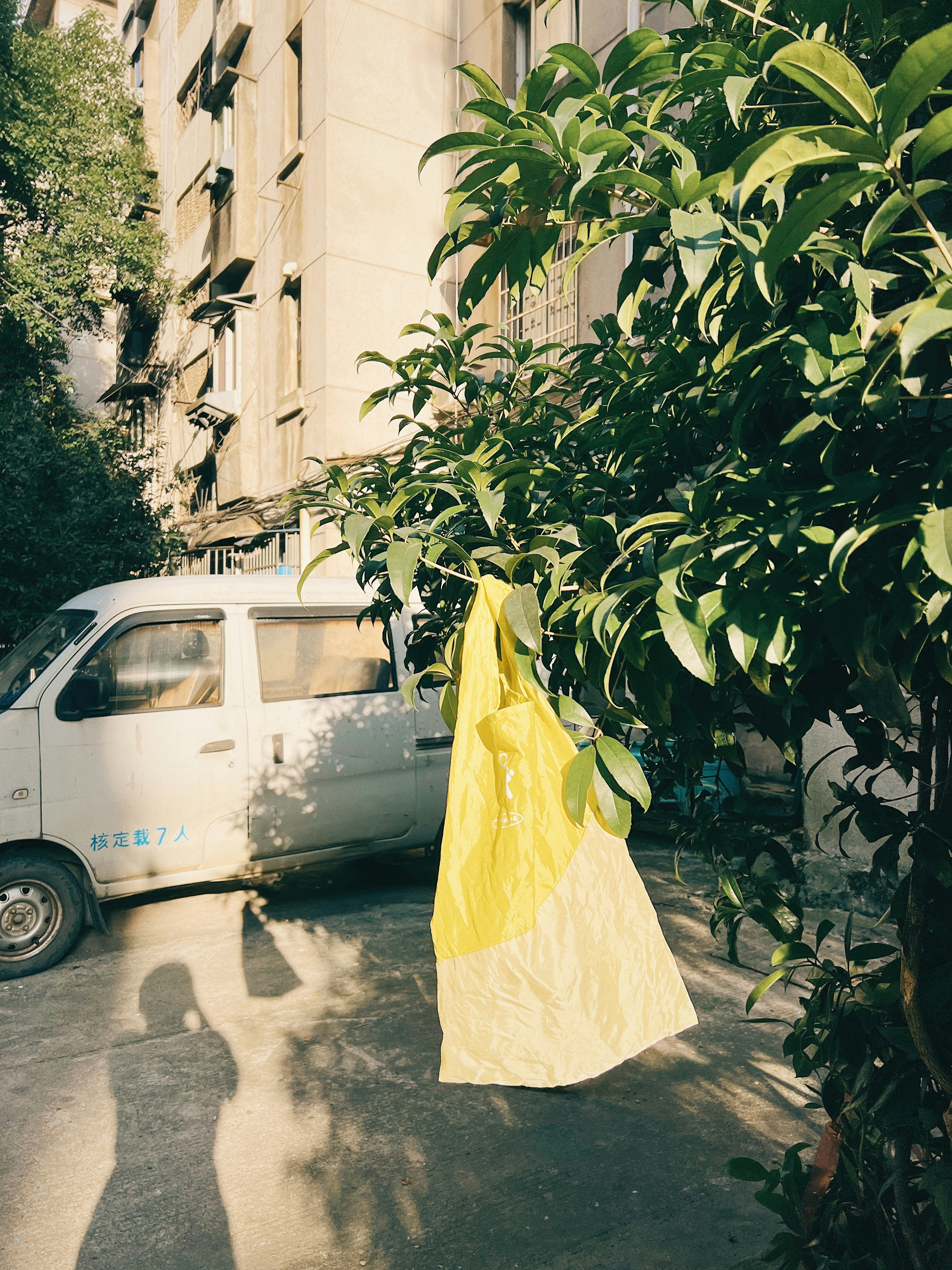 Yellow Sail Between City Facades and Greenery