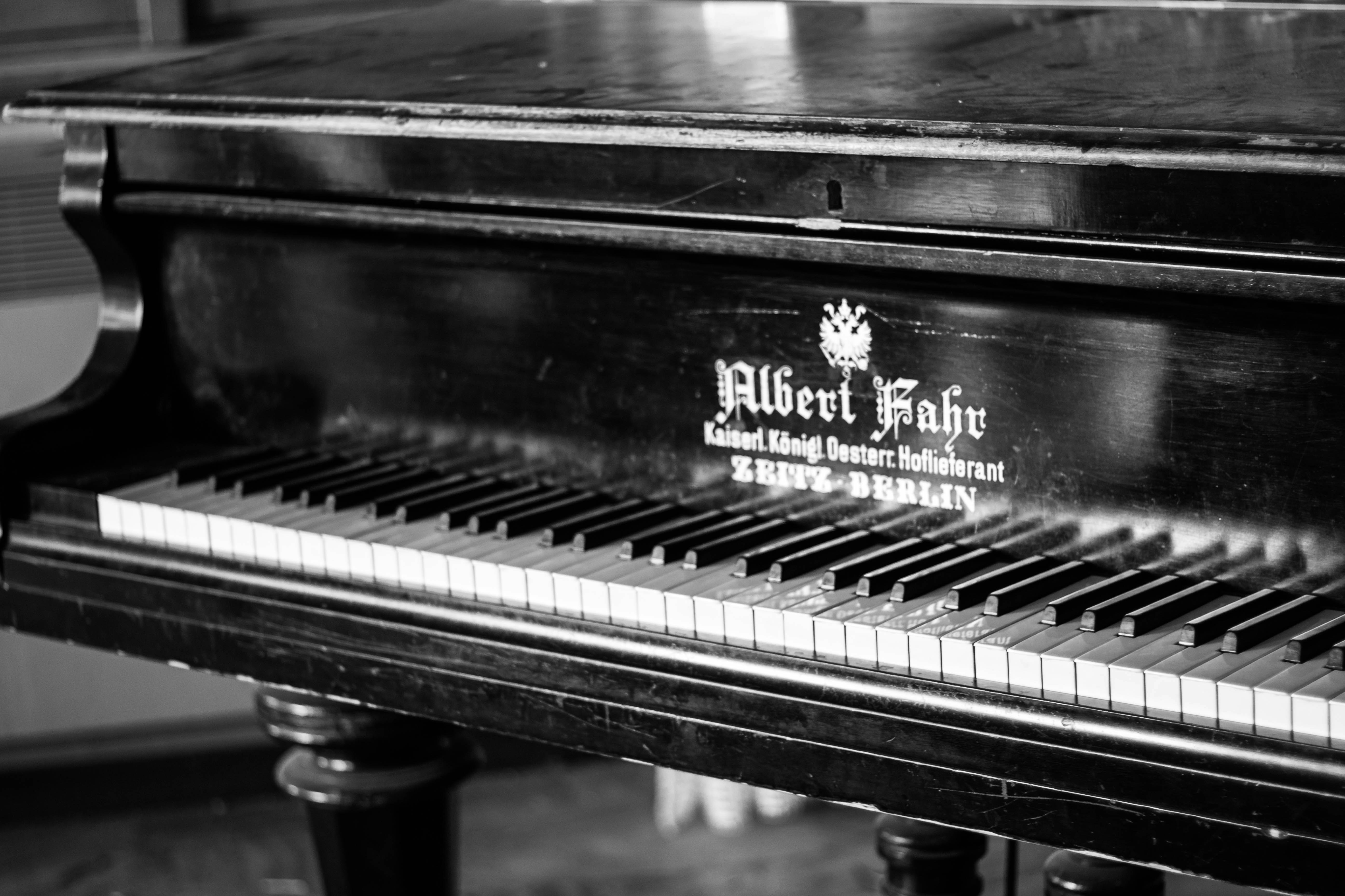 Close-up of an antique Albert Kahn piano showcasing its intricate craftsmanship and classic keys. The black and white tones enhance the vintage aesthetic.