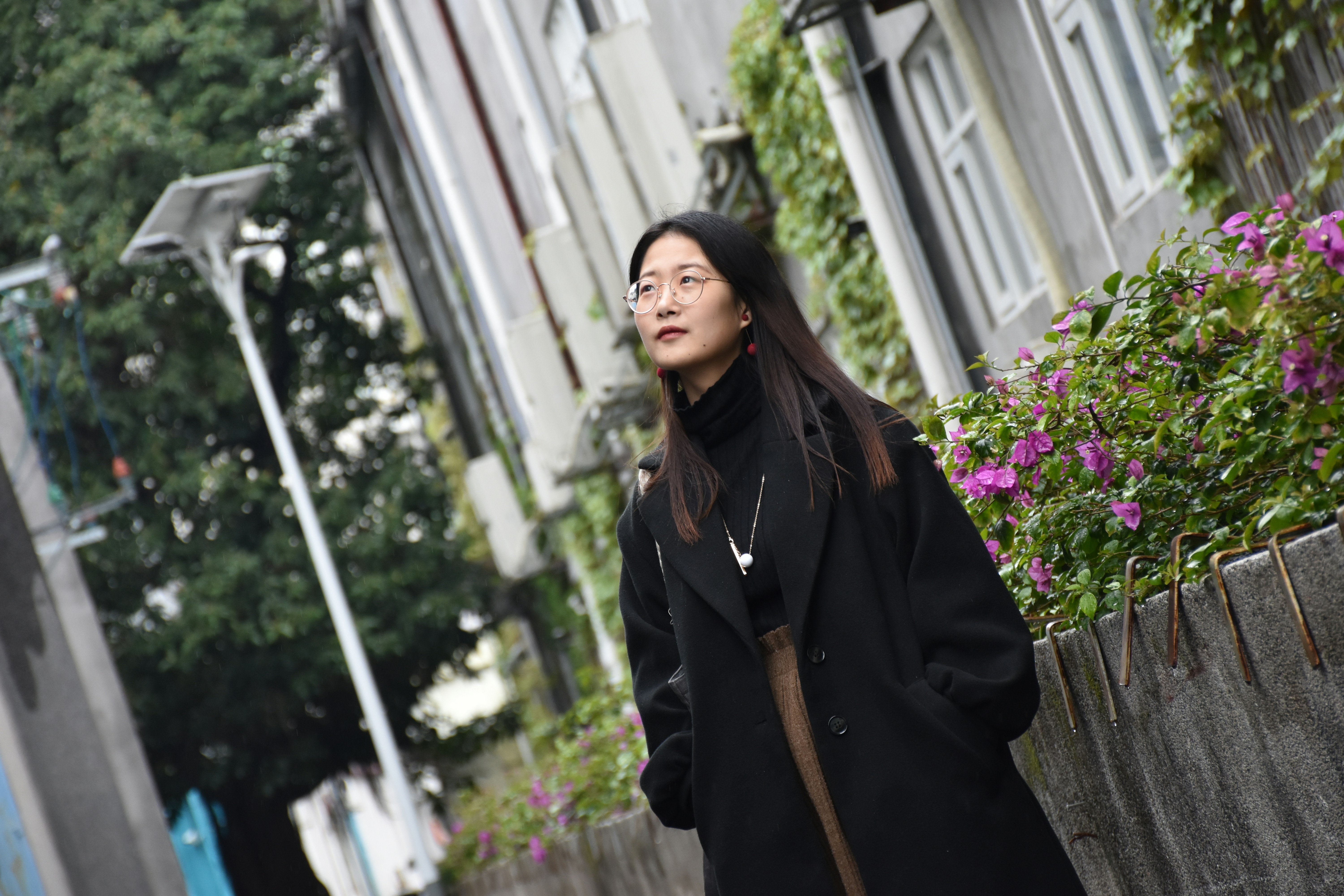 Tilted Street Portrait: Quiet Confidence Among Pink Blooms