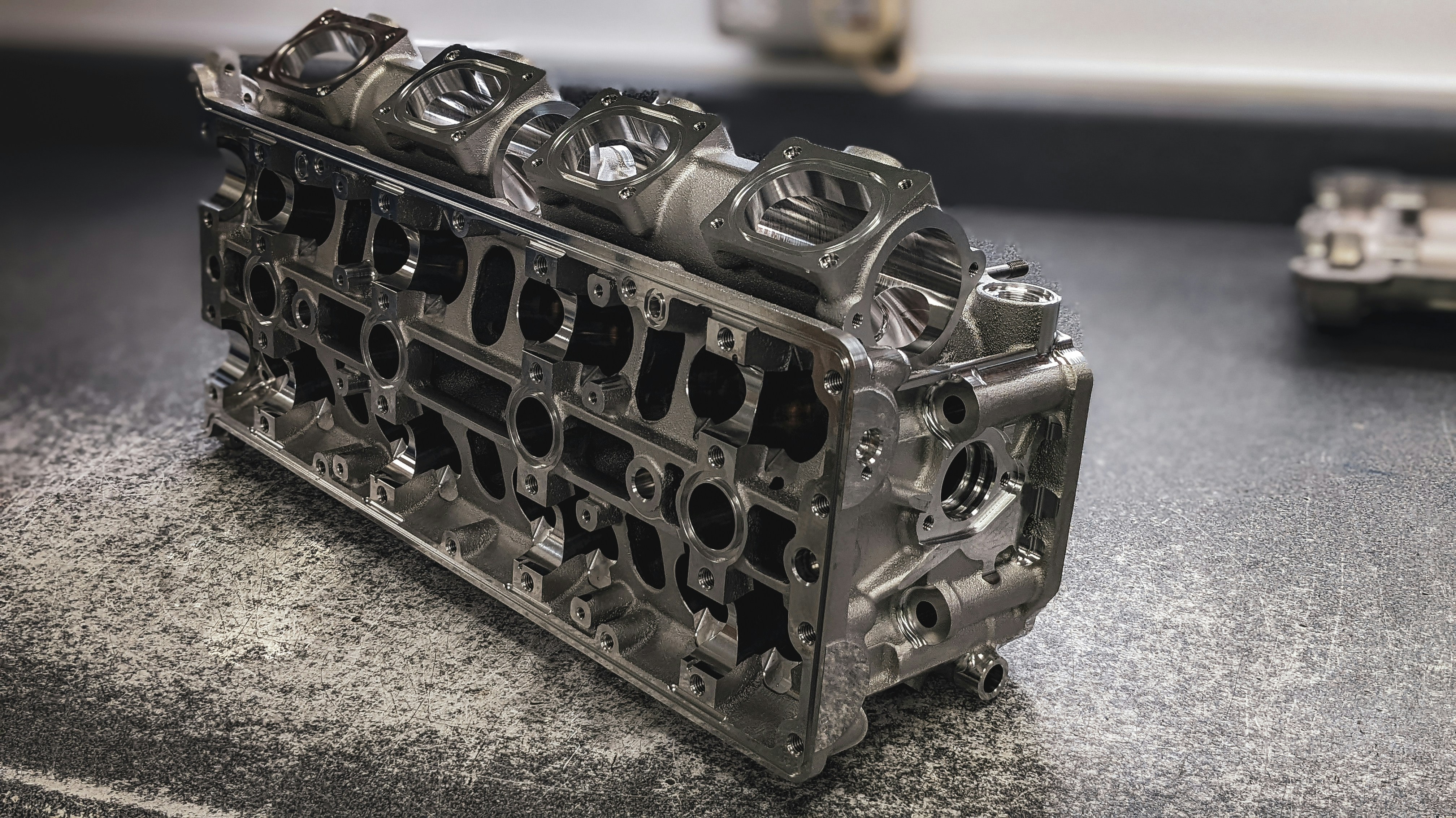 Monochrome close-up of a detailed engine block on a workshop table.