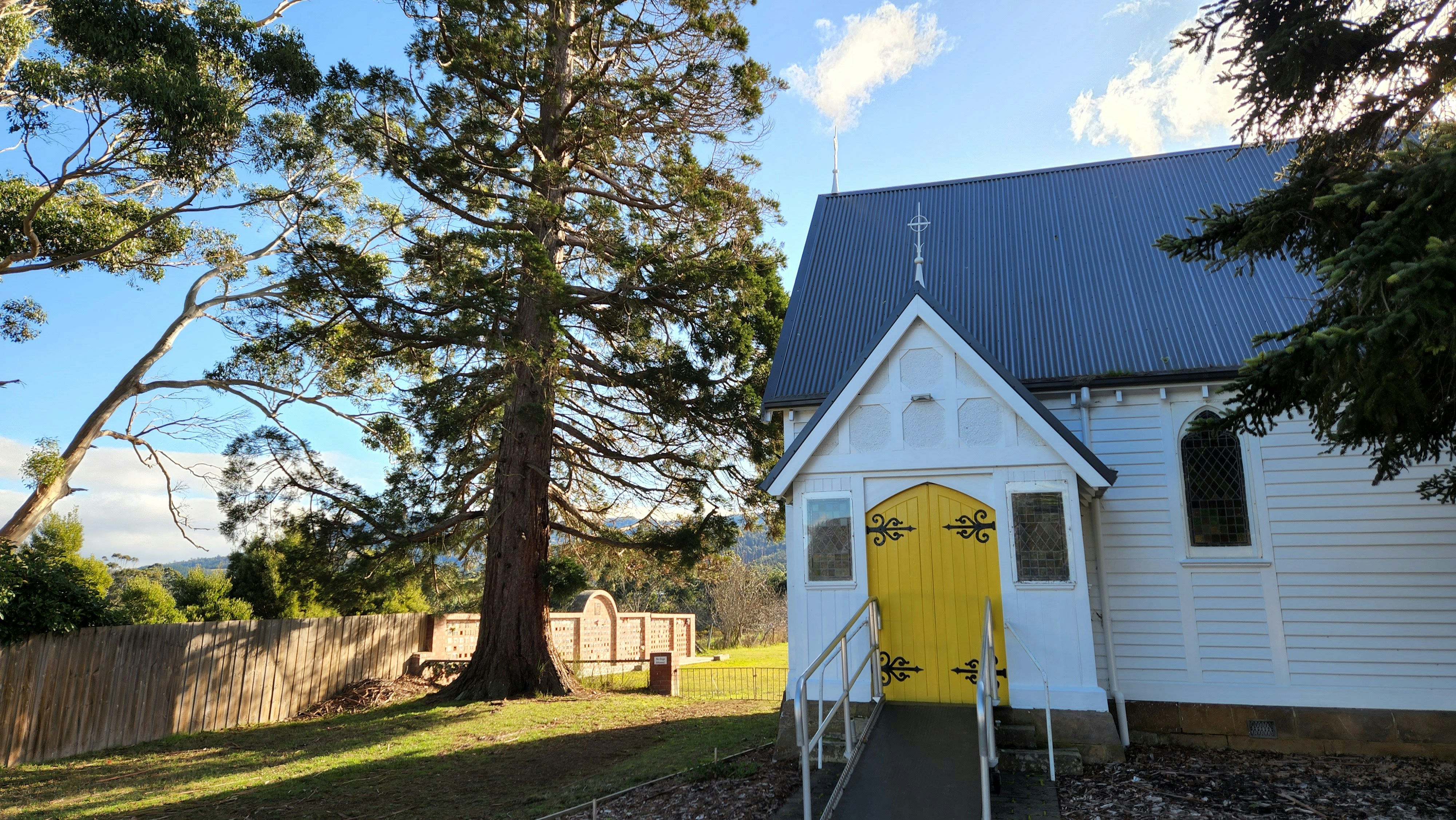 Sunlit Yellow-Door Chapel Framed by Pines