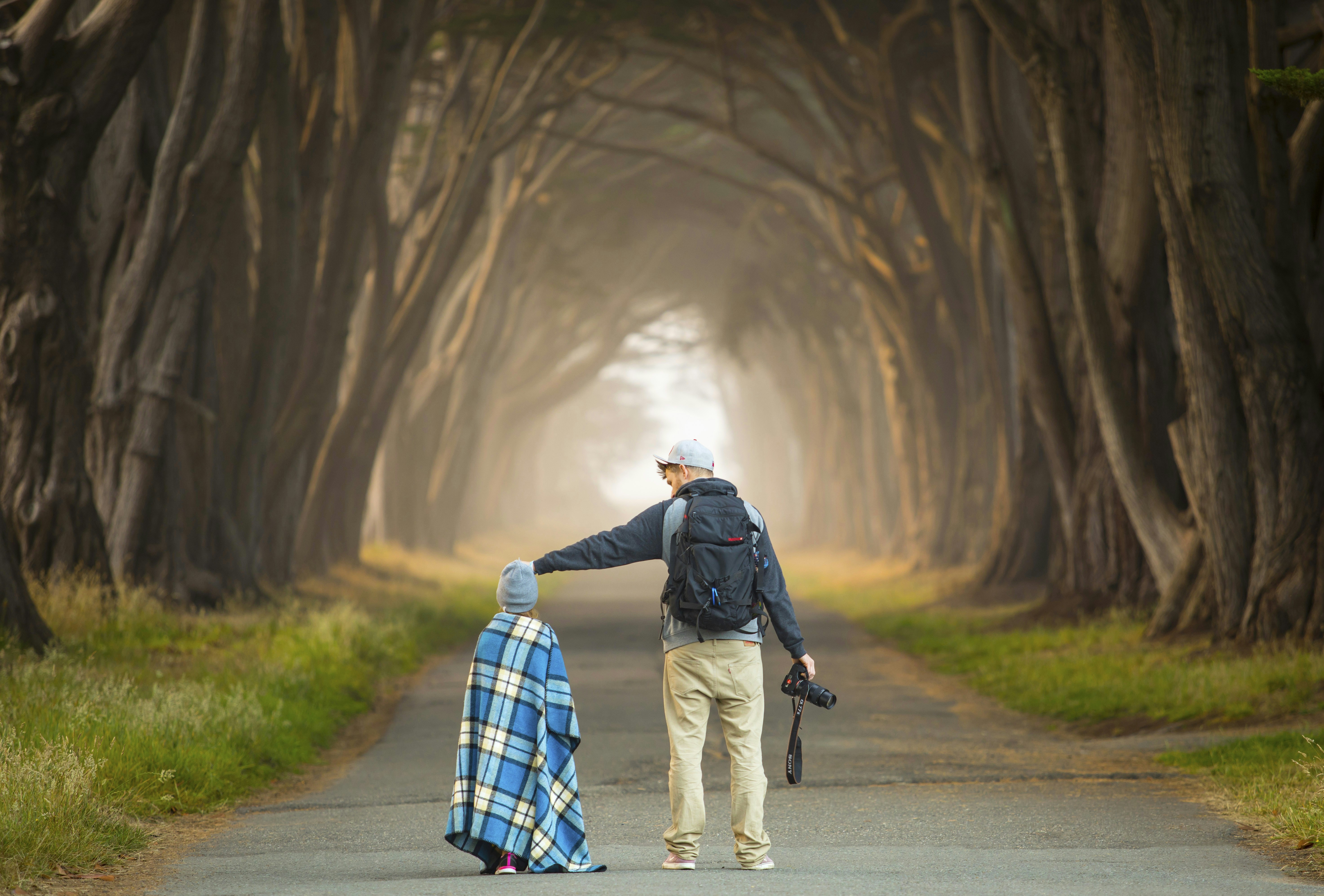 A man and woman walking on a path with a large tree photo – Free Human ...
