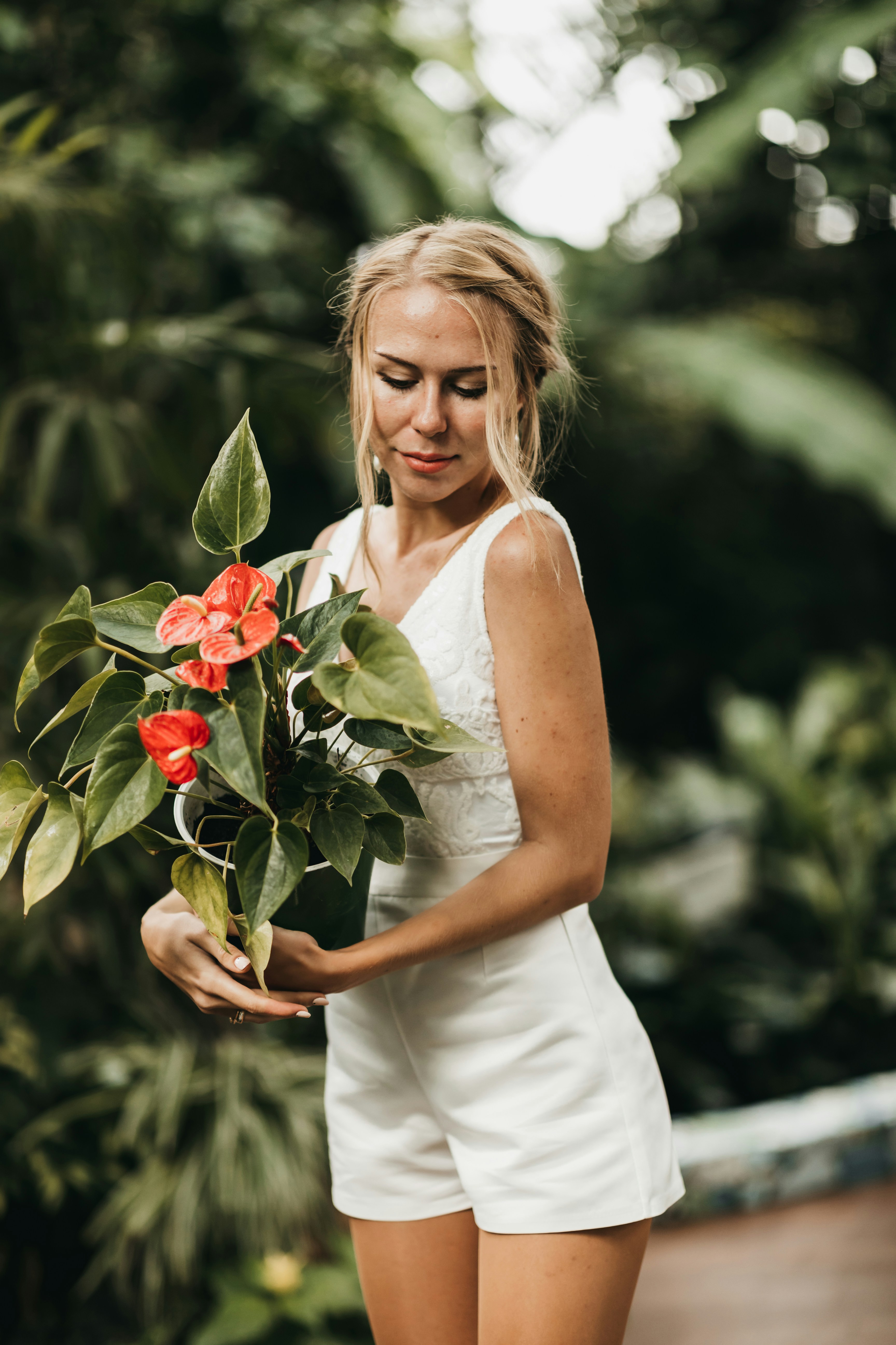 Bride in White Holds Bouquet Amid Lush Greenery