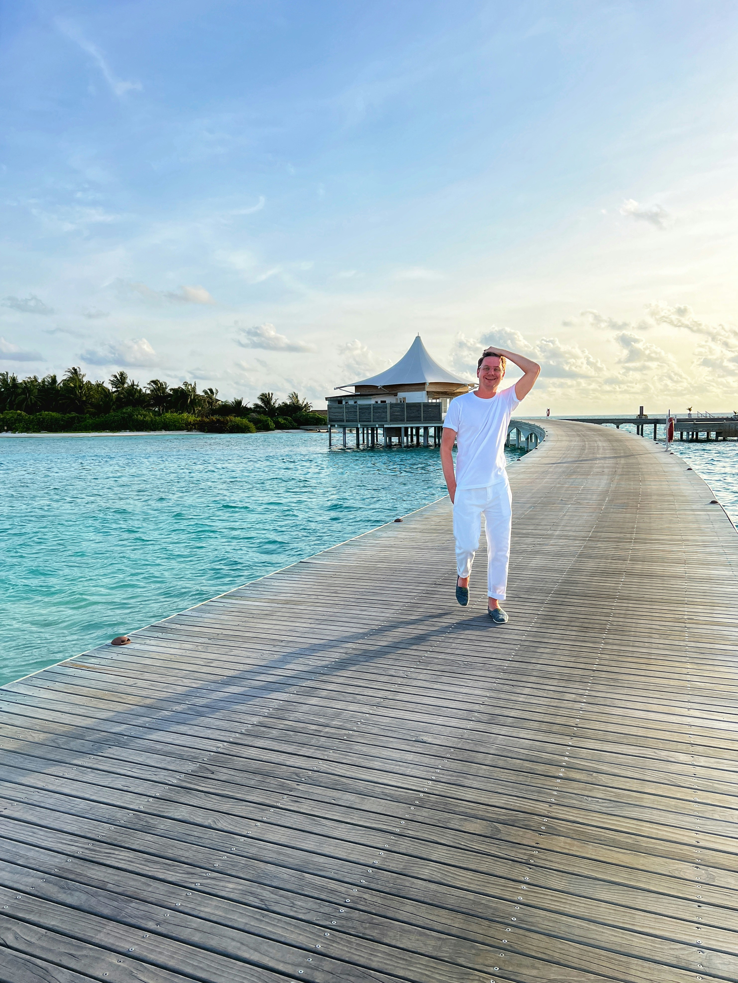 Sunlit Boardwalk: A lone wanderer on the curved pier above turquoise sea