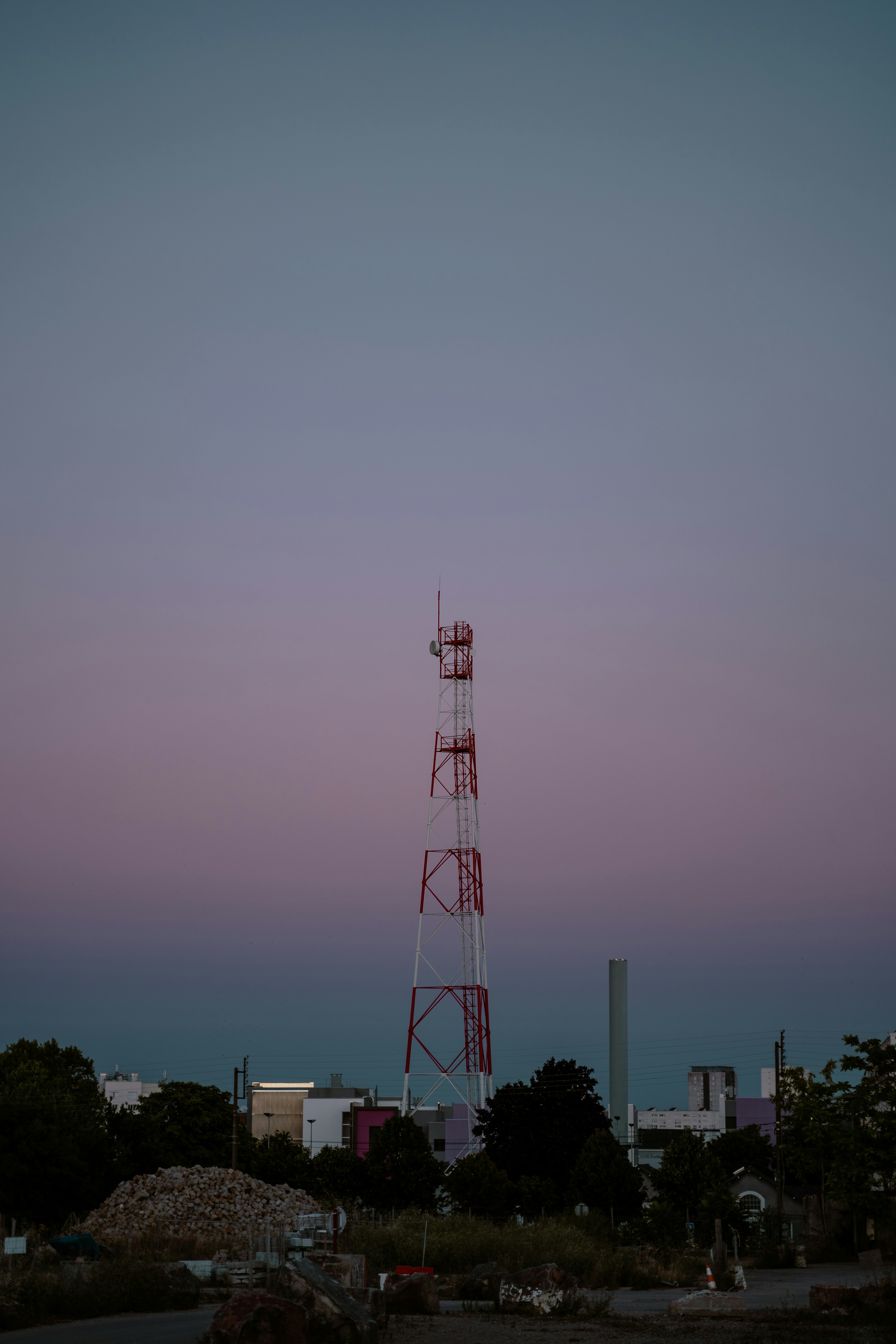 Dusk Sentinel: The Red-White Tower Rising Over a Quiet Twilight City
