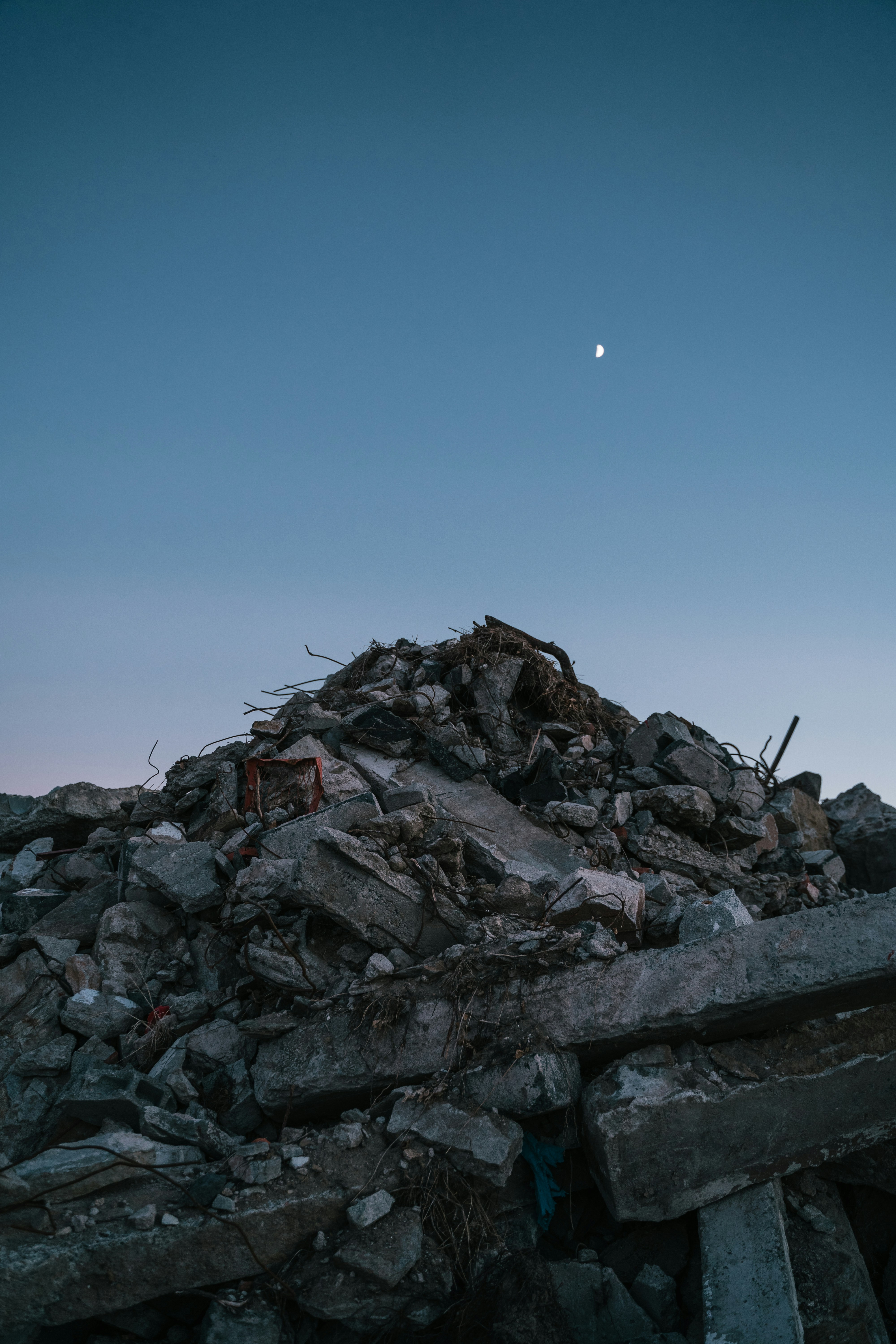Moon over Rubble: A Quiet Summit of Debris Under a Pale Sky