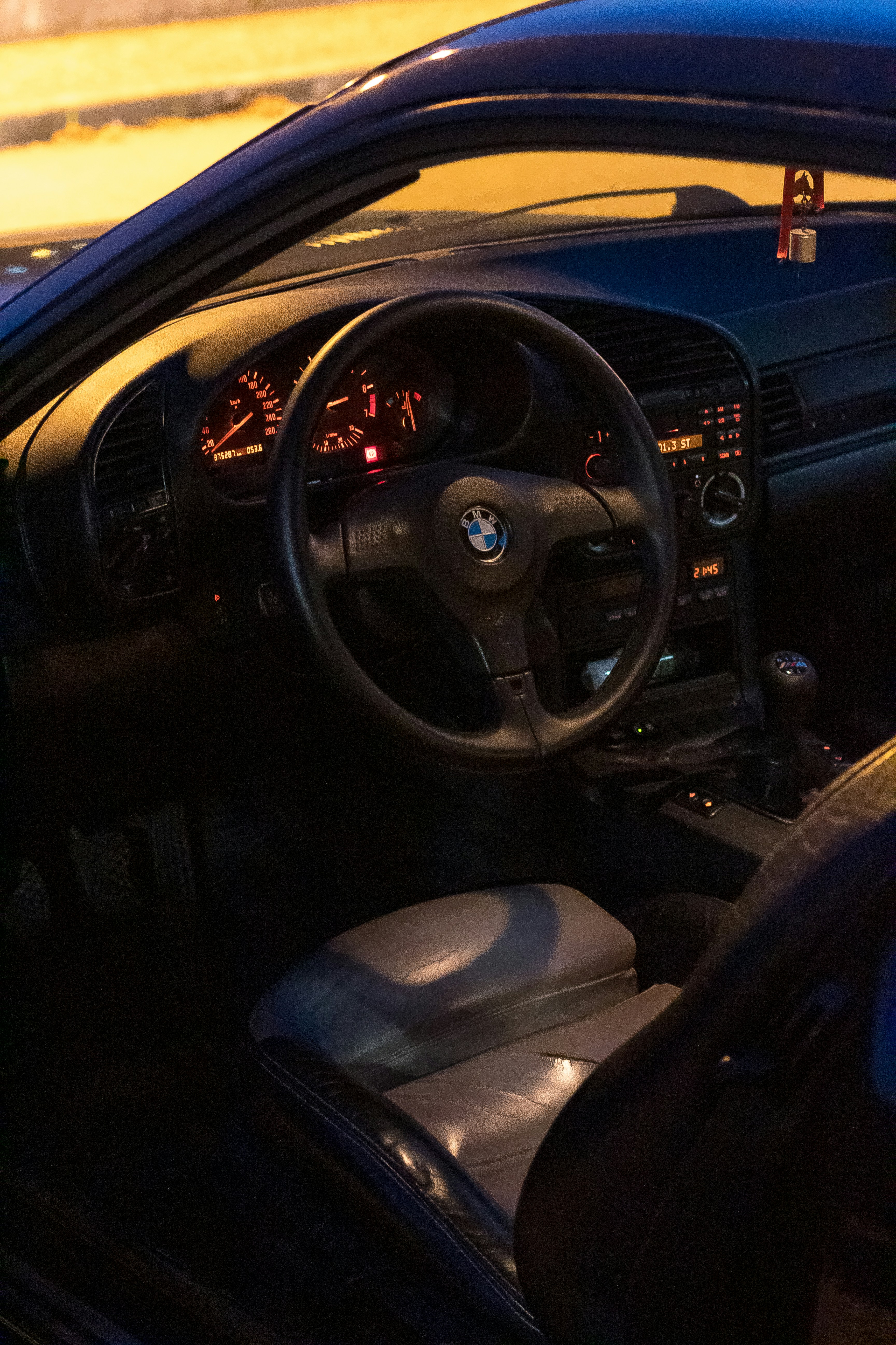 Interior view of a BMW car showcasing the steering wheel, dashboard, and leather seats illuminated by ambient lighting.