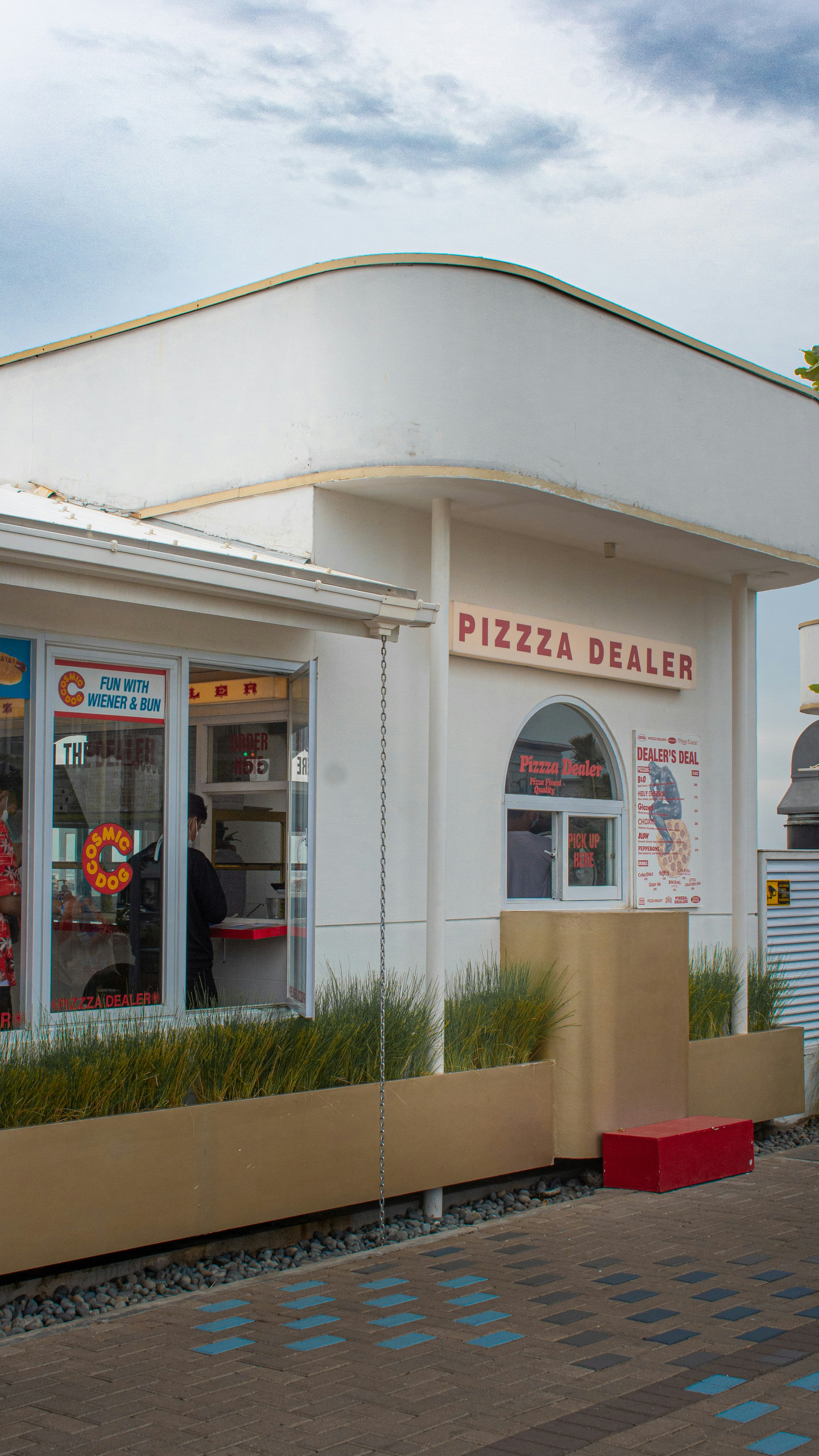 Modern pizza stand featuring a vibrant menu and inviting design, set against a backdrop of casual dining. The establishment emphasizes a fun atmosphere for food lovers.
