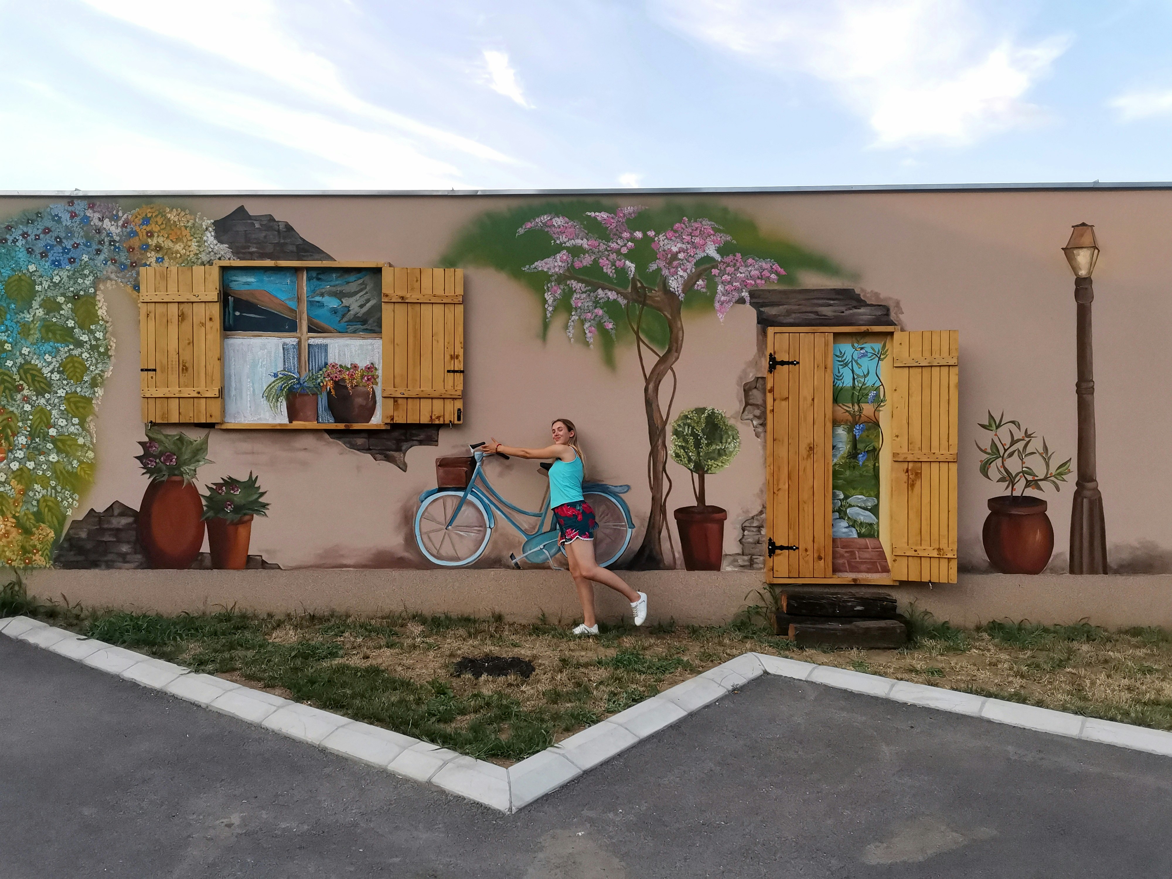 Runner by a muraled wall: a jogger pauses with a bike amid painted blooms
