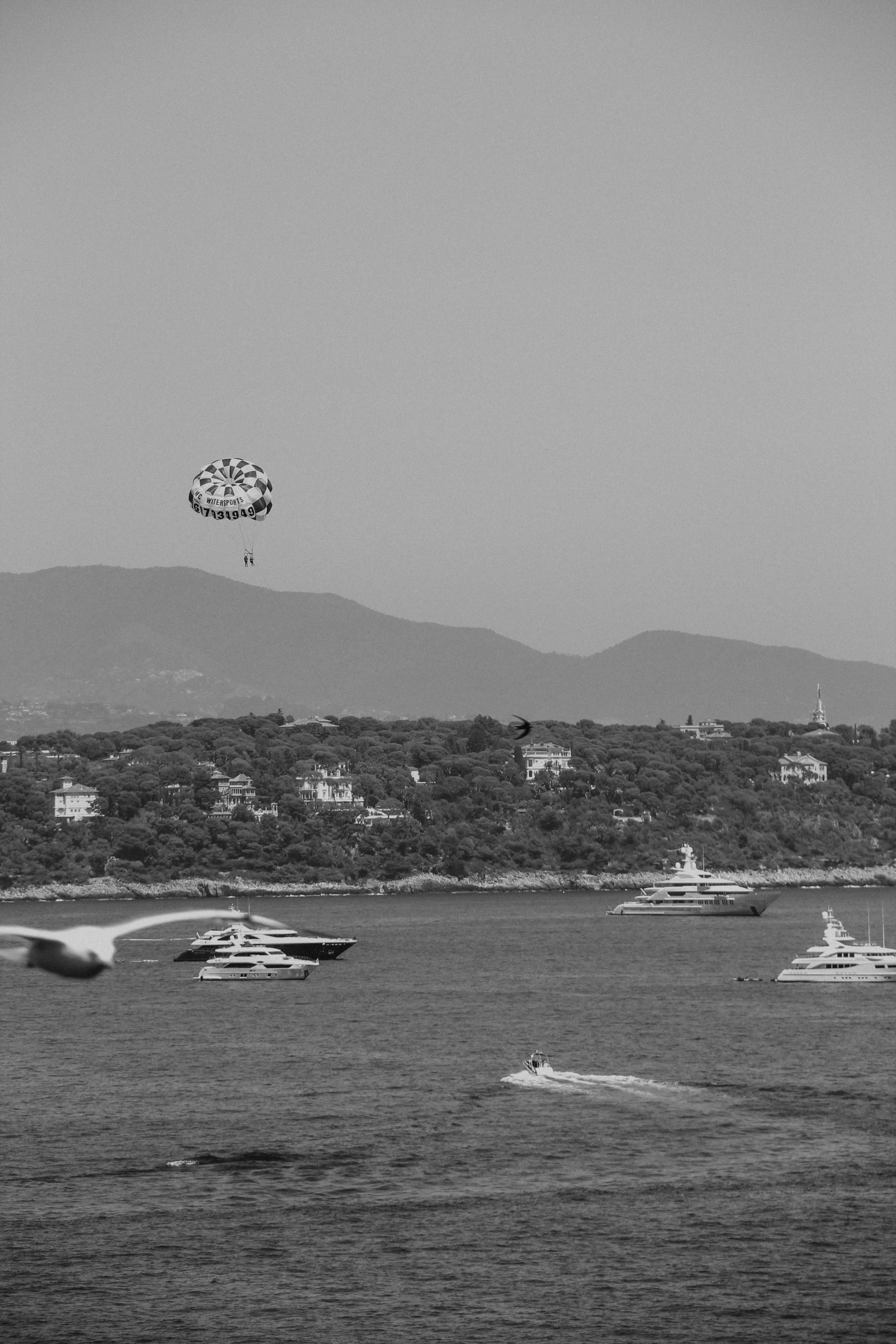 Parasail over the bay: distant shoreline and yachts under calm skies