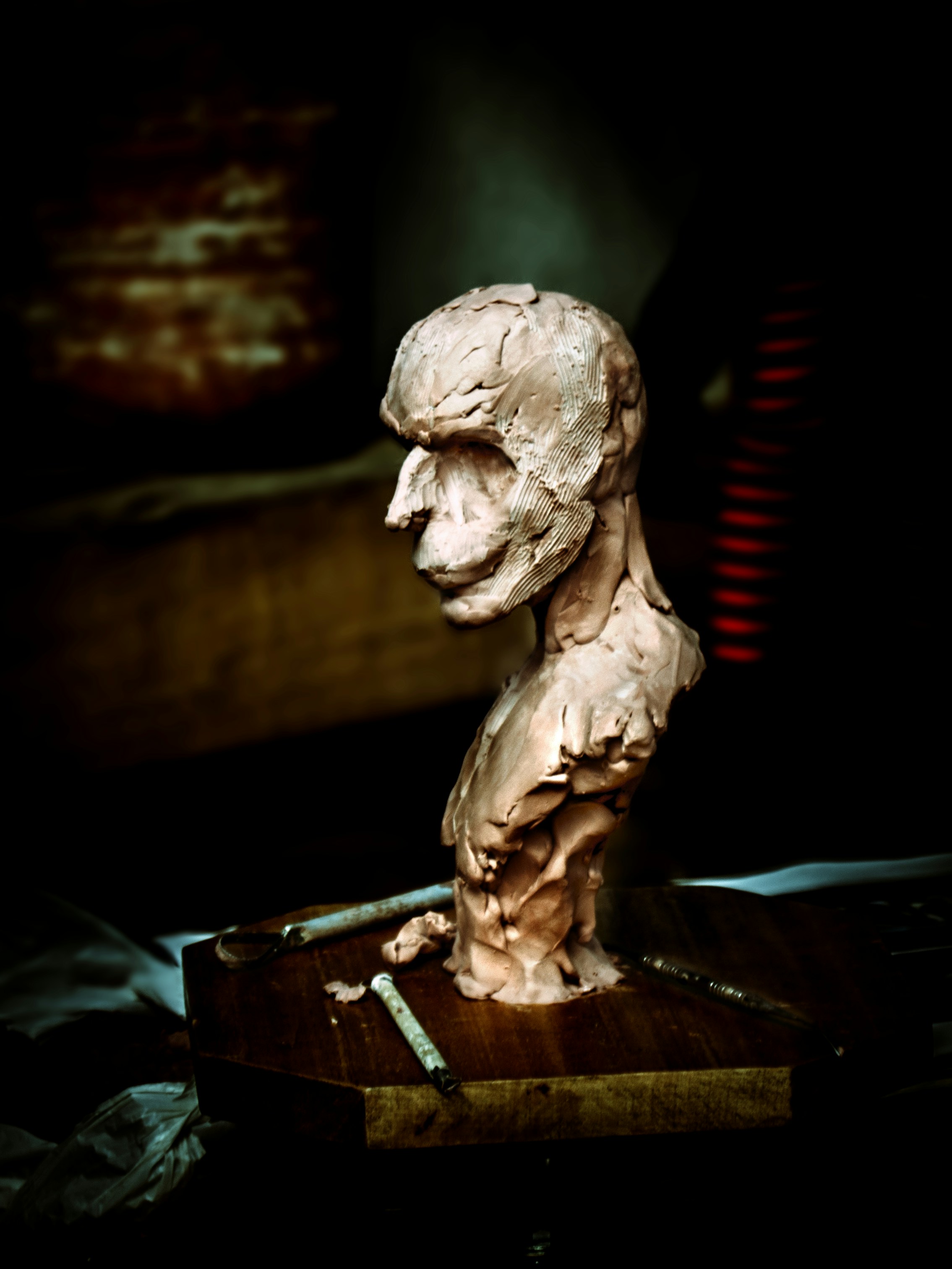Shadowed Flesh: A Luminous Clay Bust Poised in a Dim Studio