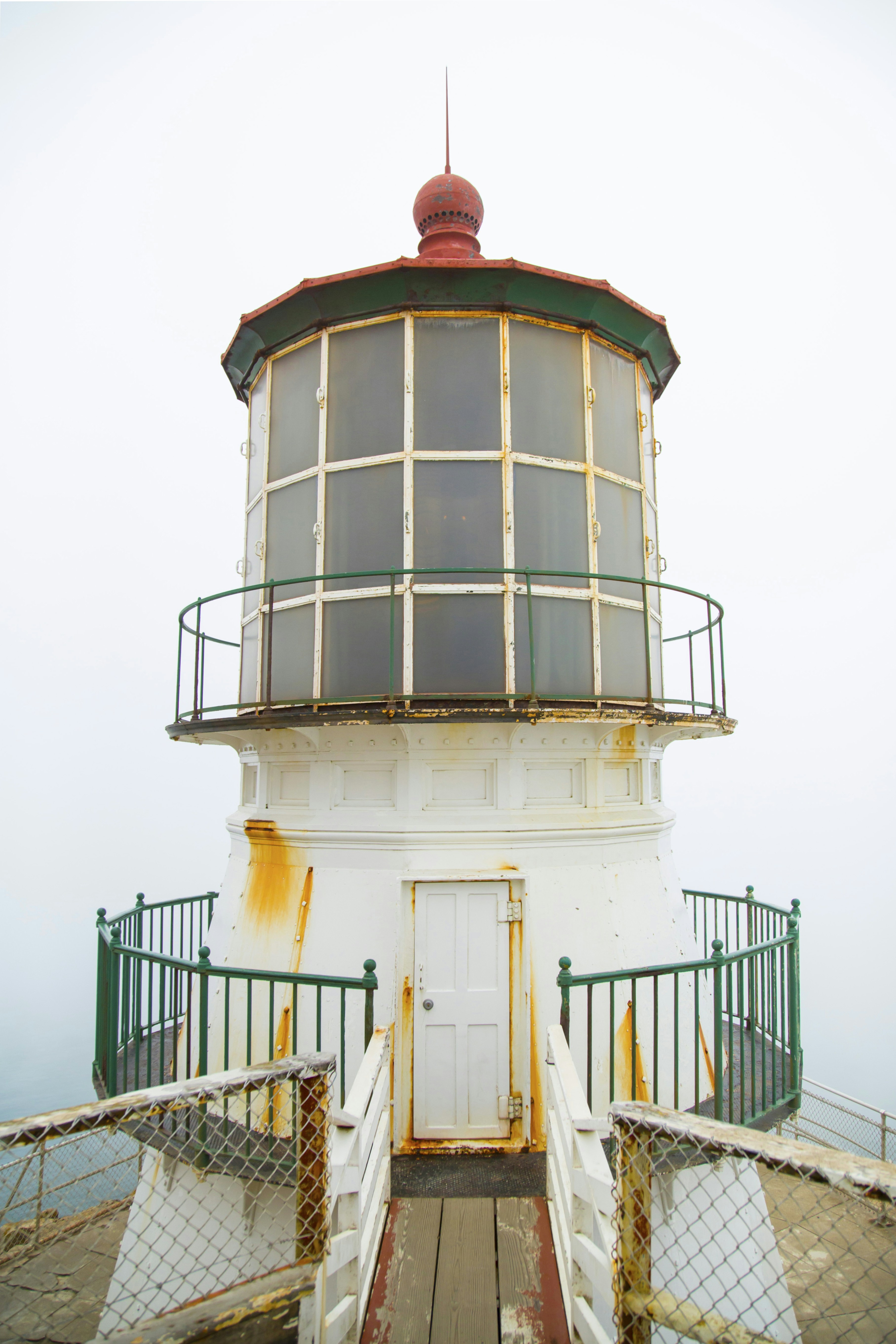 Rust and Glass at the Edge: A Clifftop Lighthouse in Morning Mist
