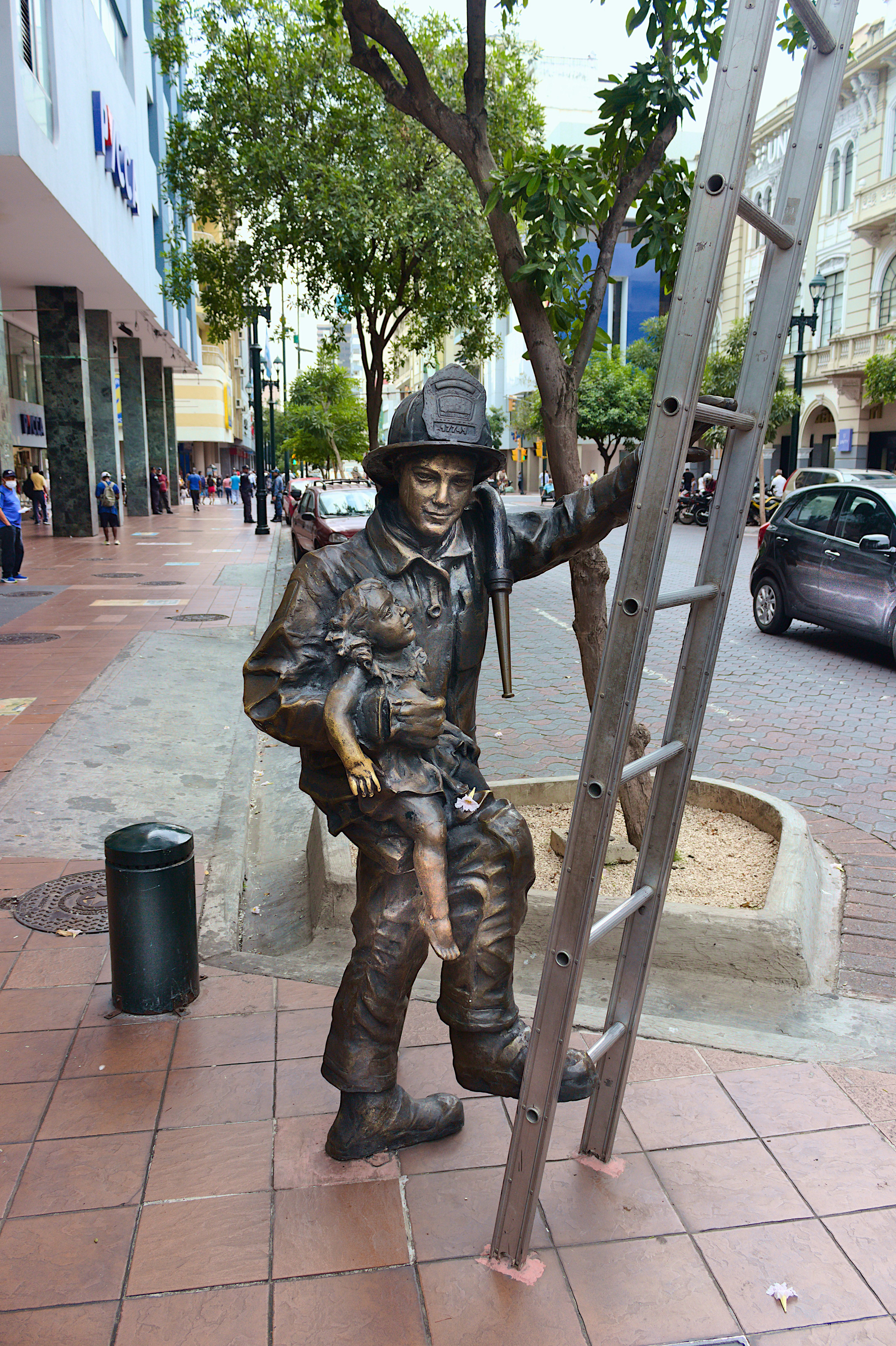 Bronze Firefighter and Child: A Street-Side Sentinel Beside a Leaning Ladder