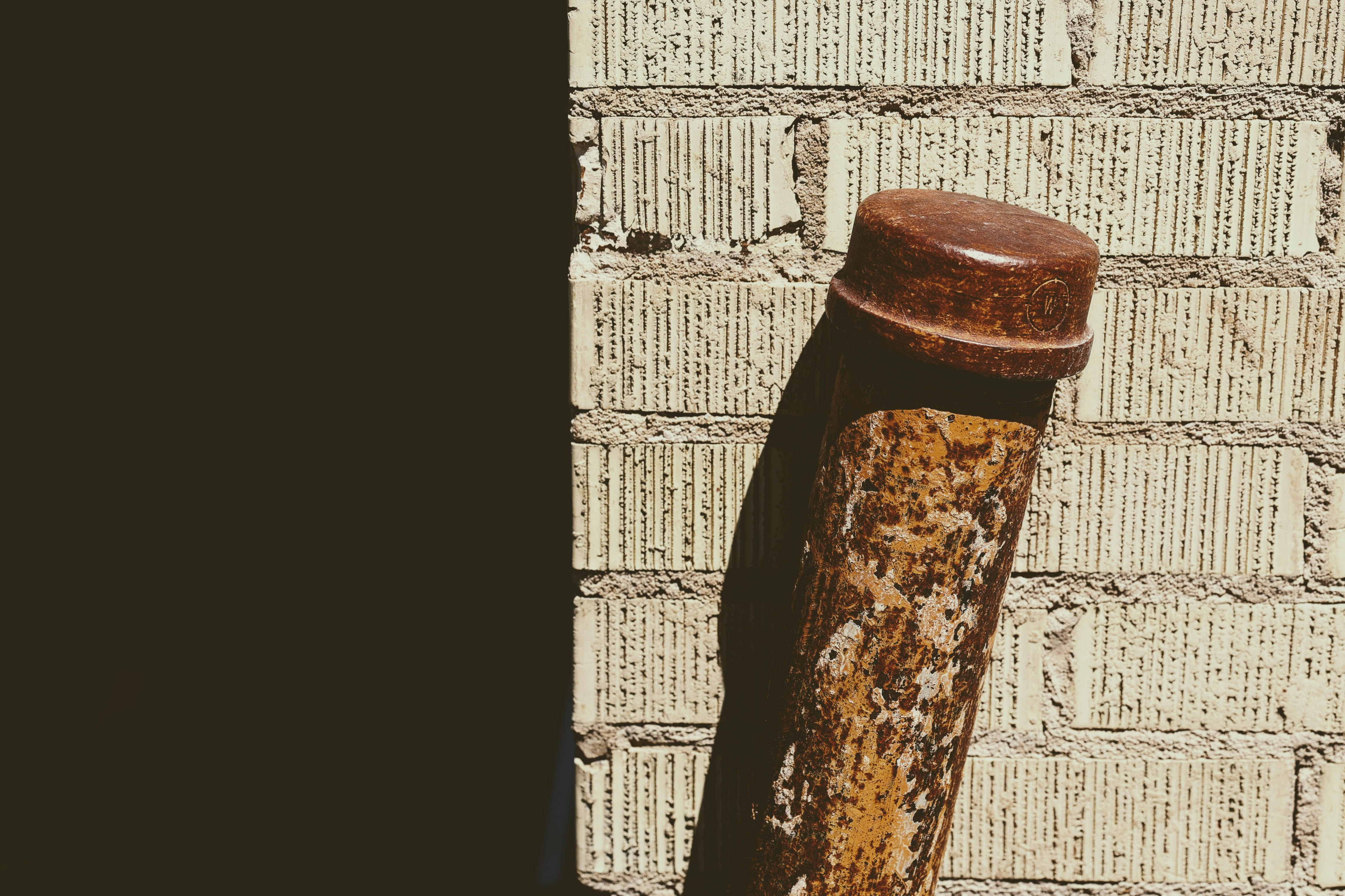 Rusty Cylinder Against a Brick Wall