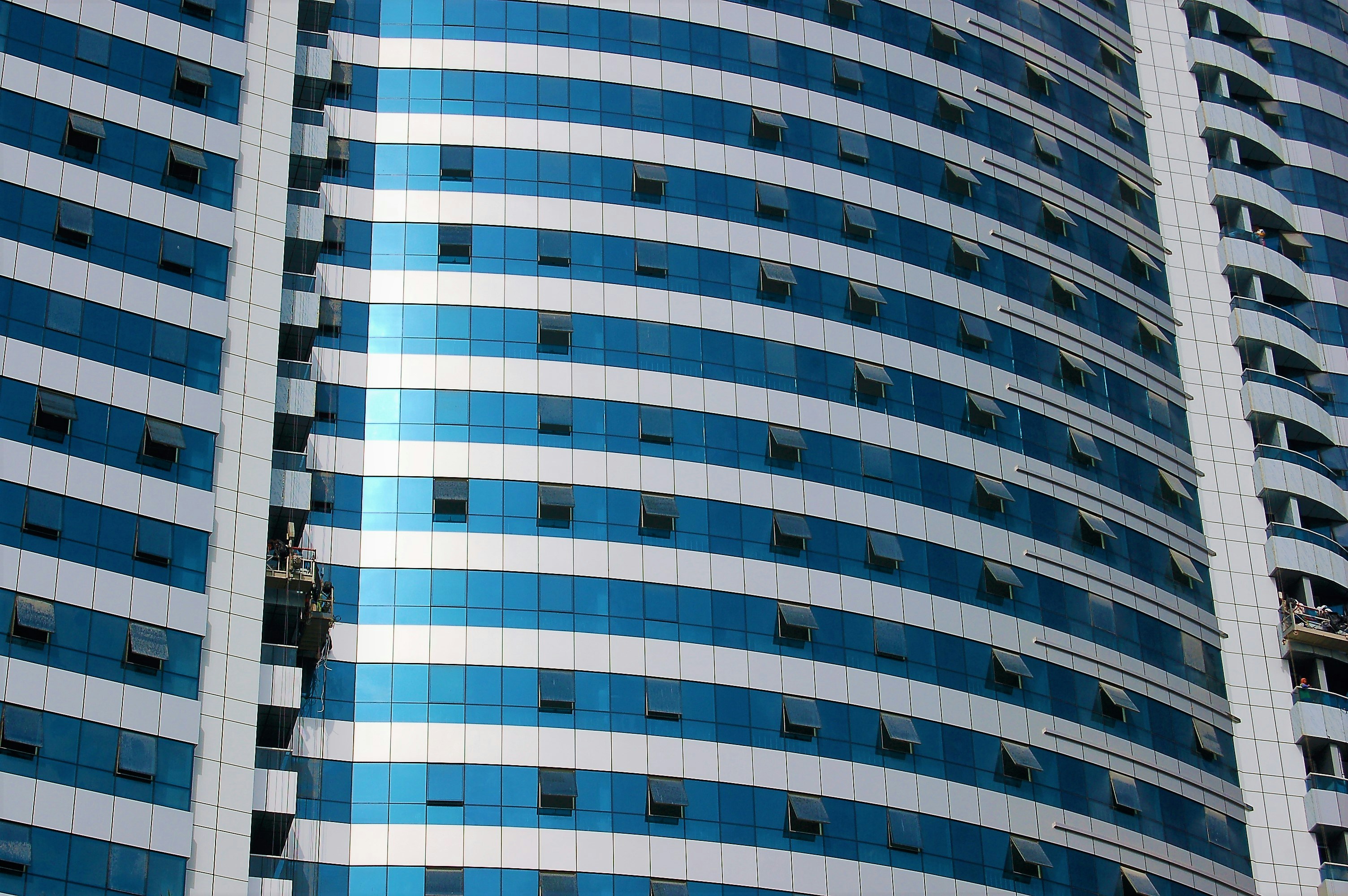 Curved facade of a modern high-rise with alternating blue and white stripes.