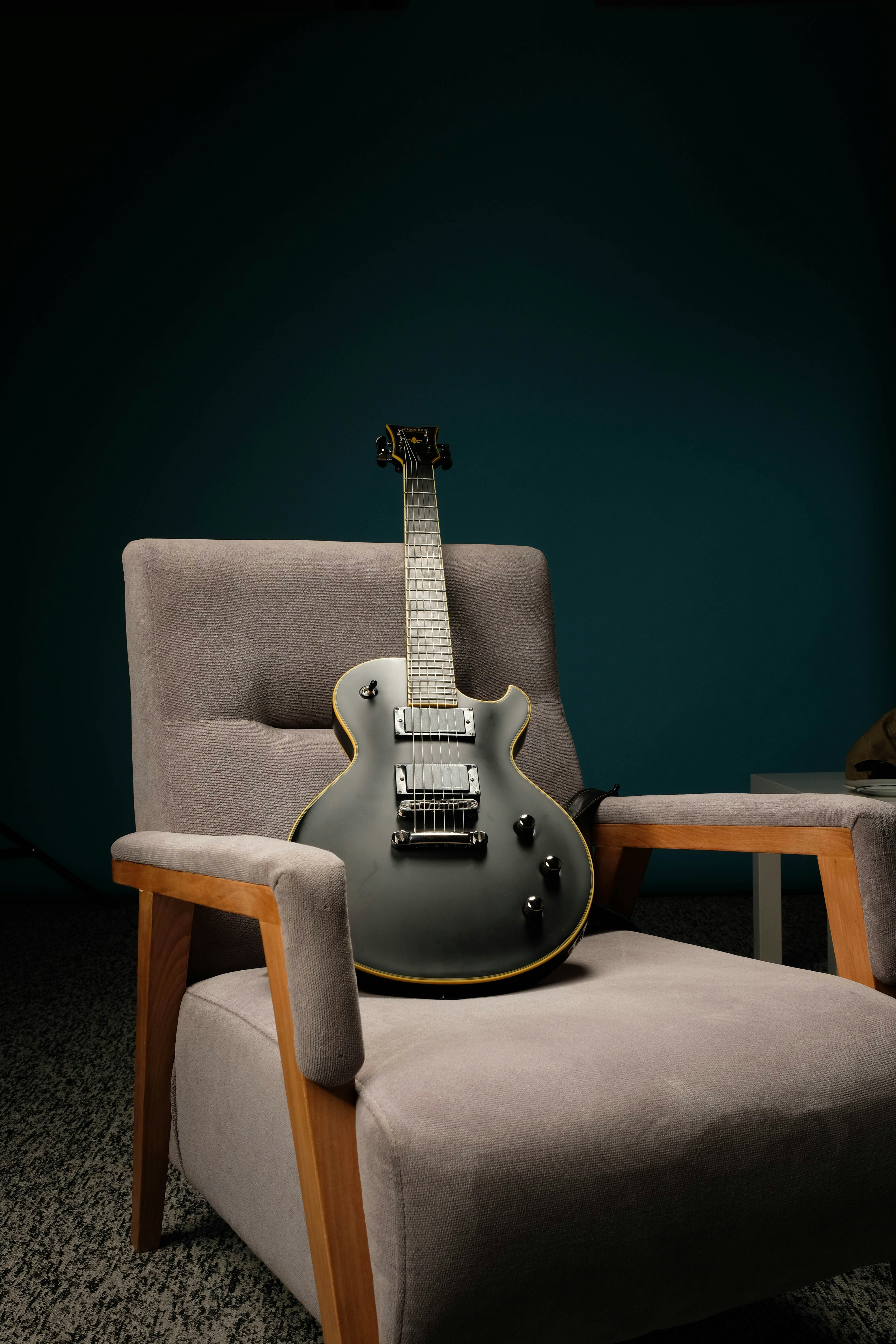 A sleek electric guitar rests elegantly on a modern armchair, surrounded by a minimalist interior. The contrasting colors enhance the guitar's design.
