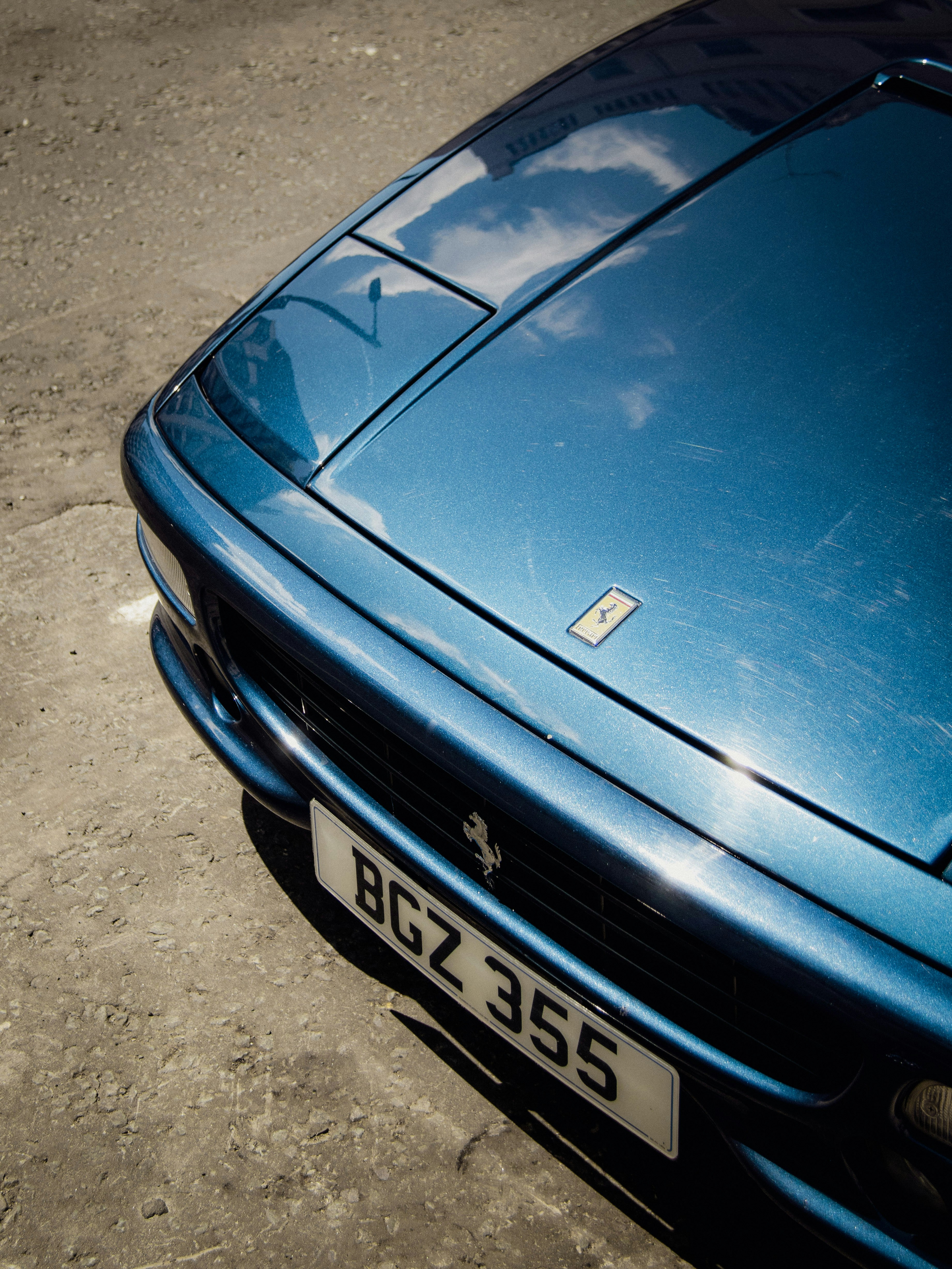 Azure Ferrari Hood: Emblem Glint and Sky-Reflected Curves