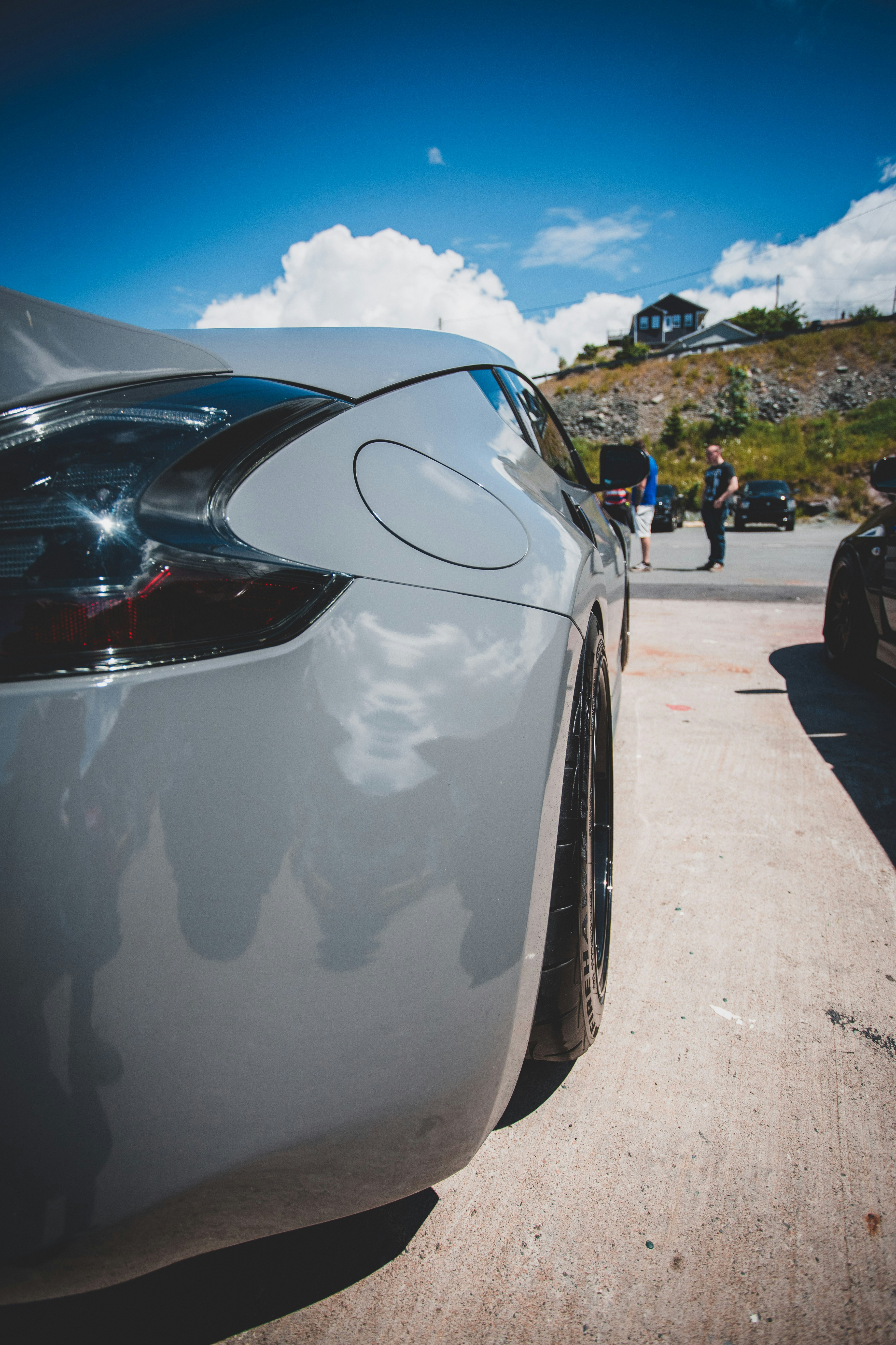 A silver sports car parked on a road with people walking around photo ...