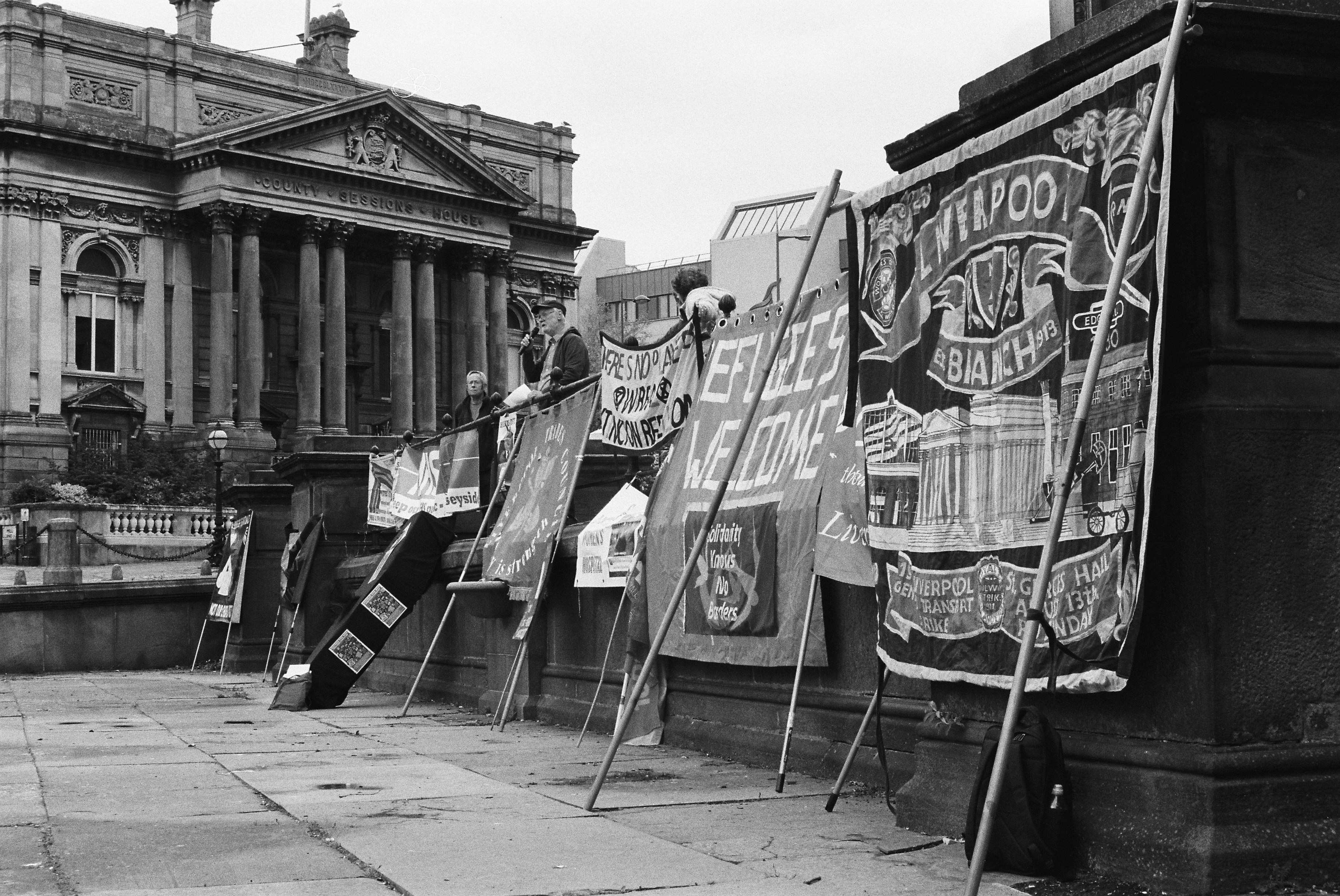 Banners along a city plaza: protest signs framing classical architecture