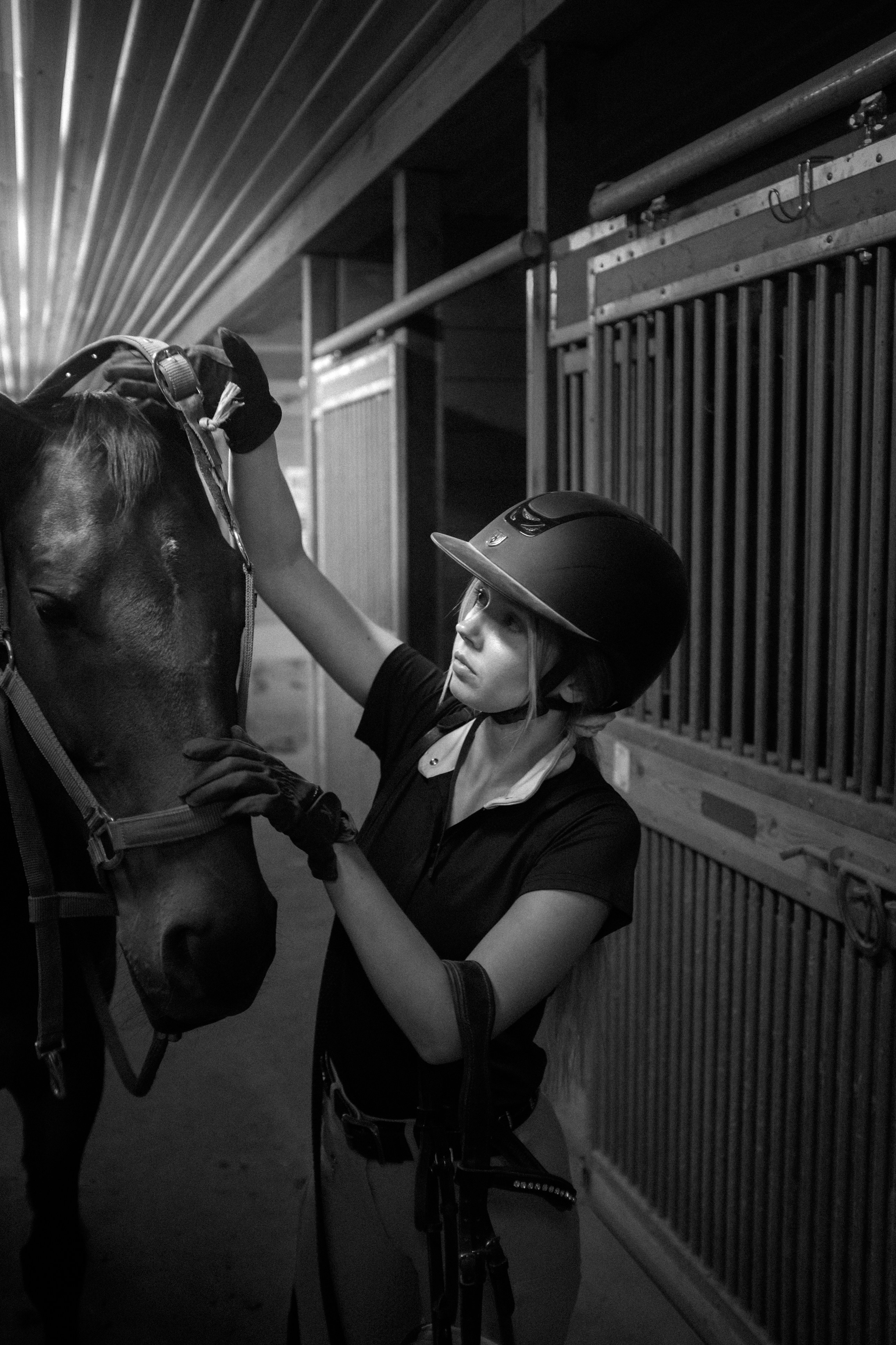 Quiet Bond in Black and White: A Rider Tends Her Horse in the Stable