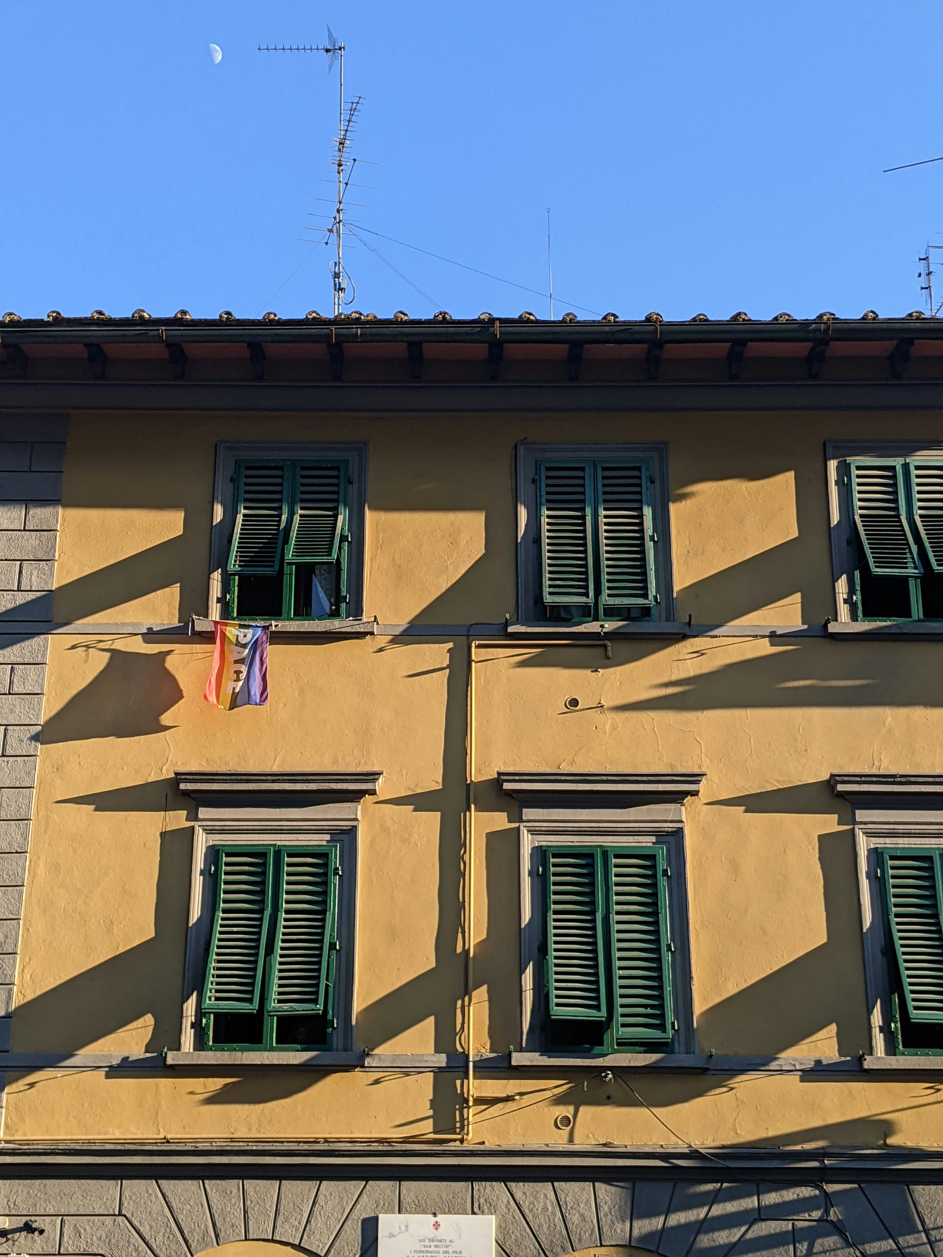Sunlit Yellow Facade with Verdant Shutters and Angular Shadows