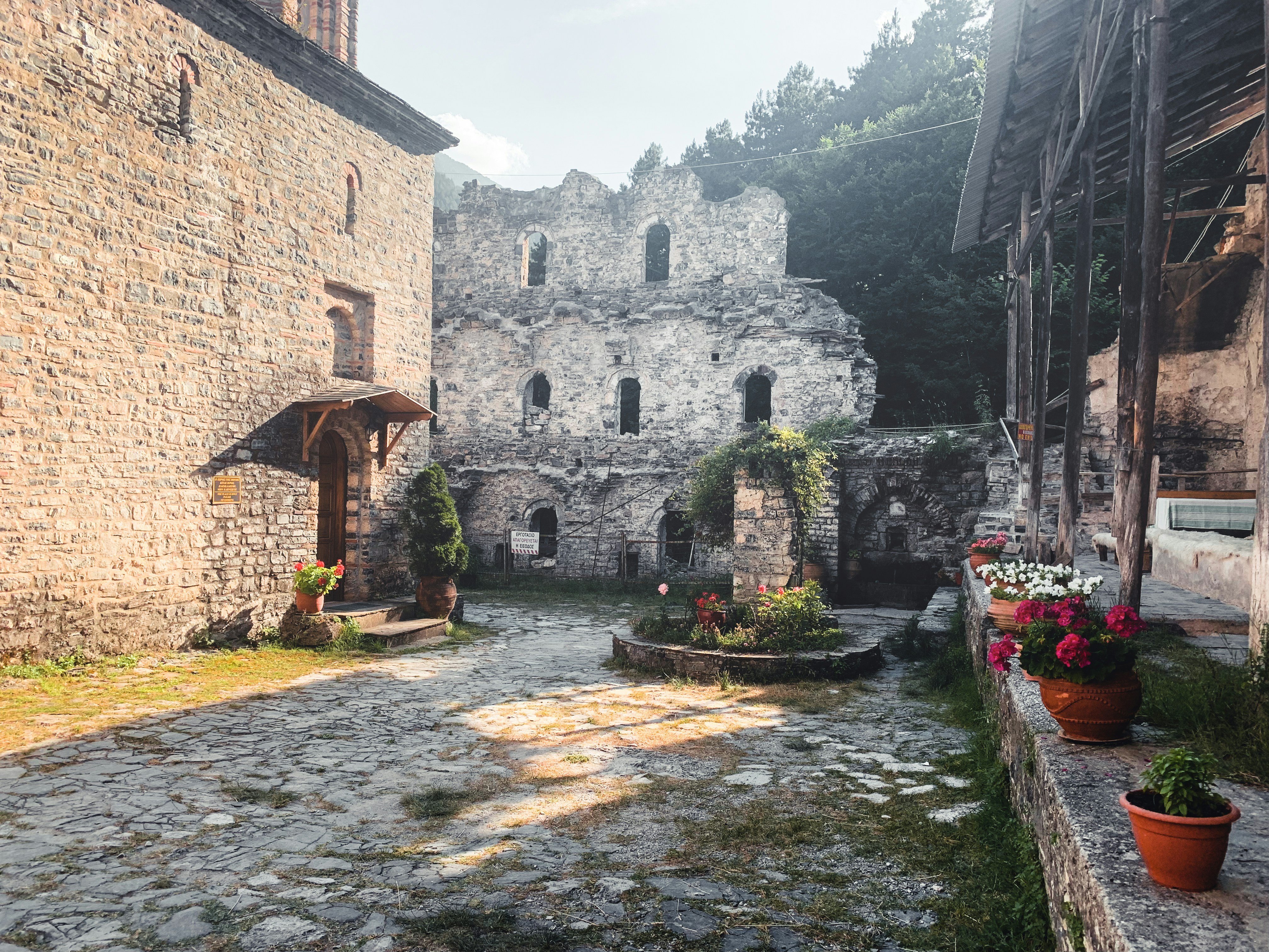Monastery near the mount Olymp | a stone courtyard with buildings and flowers